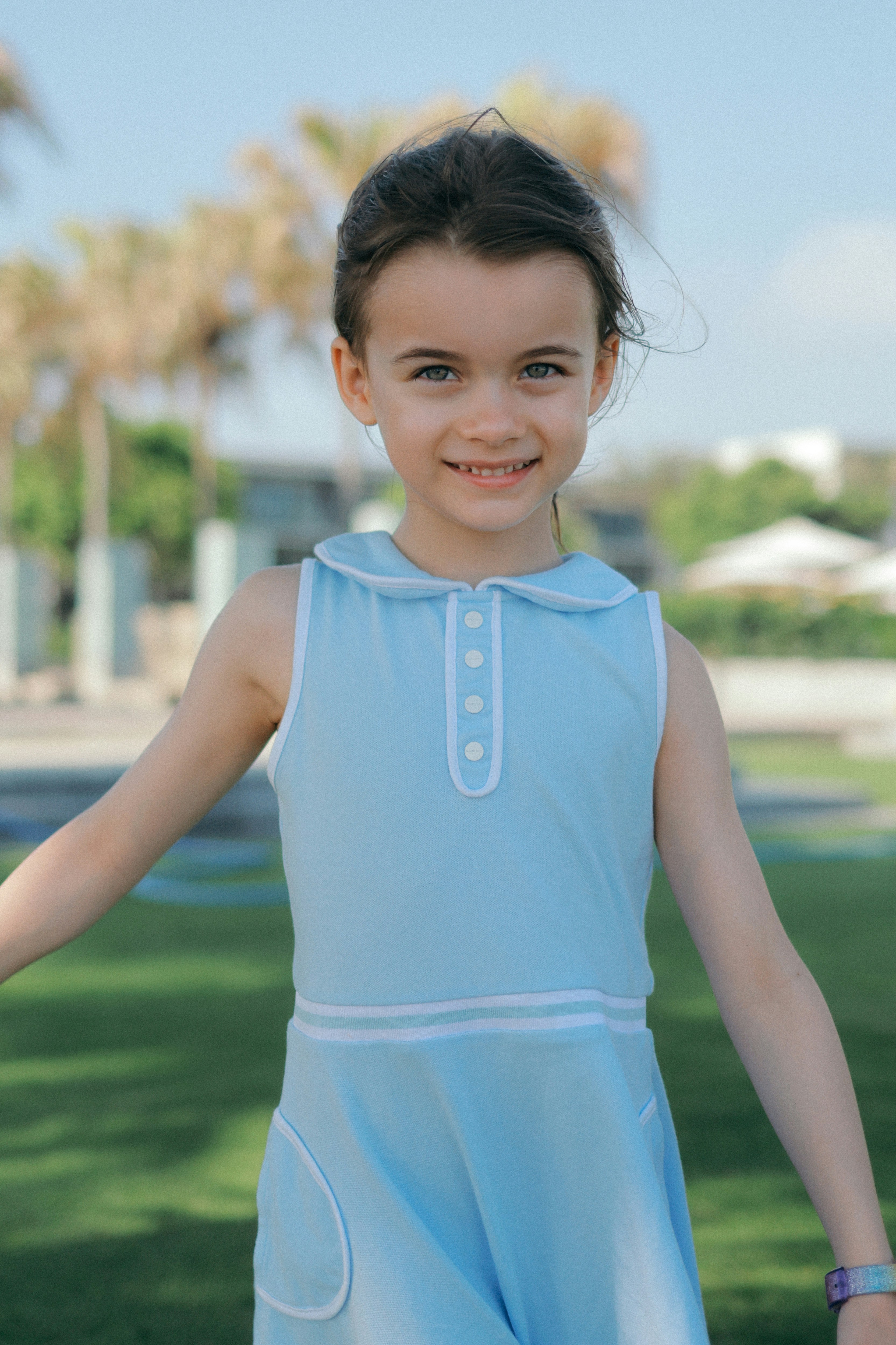 Sunlit Smile: A Girl in a Light Blue Dress Outdoors
