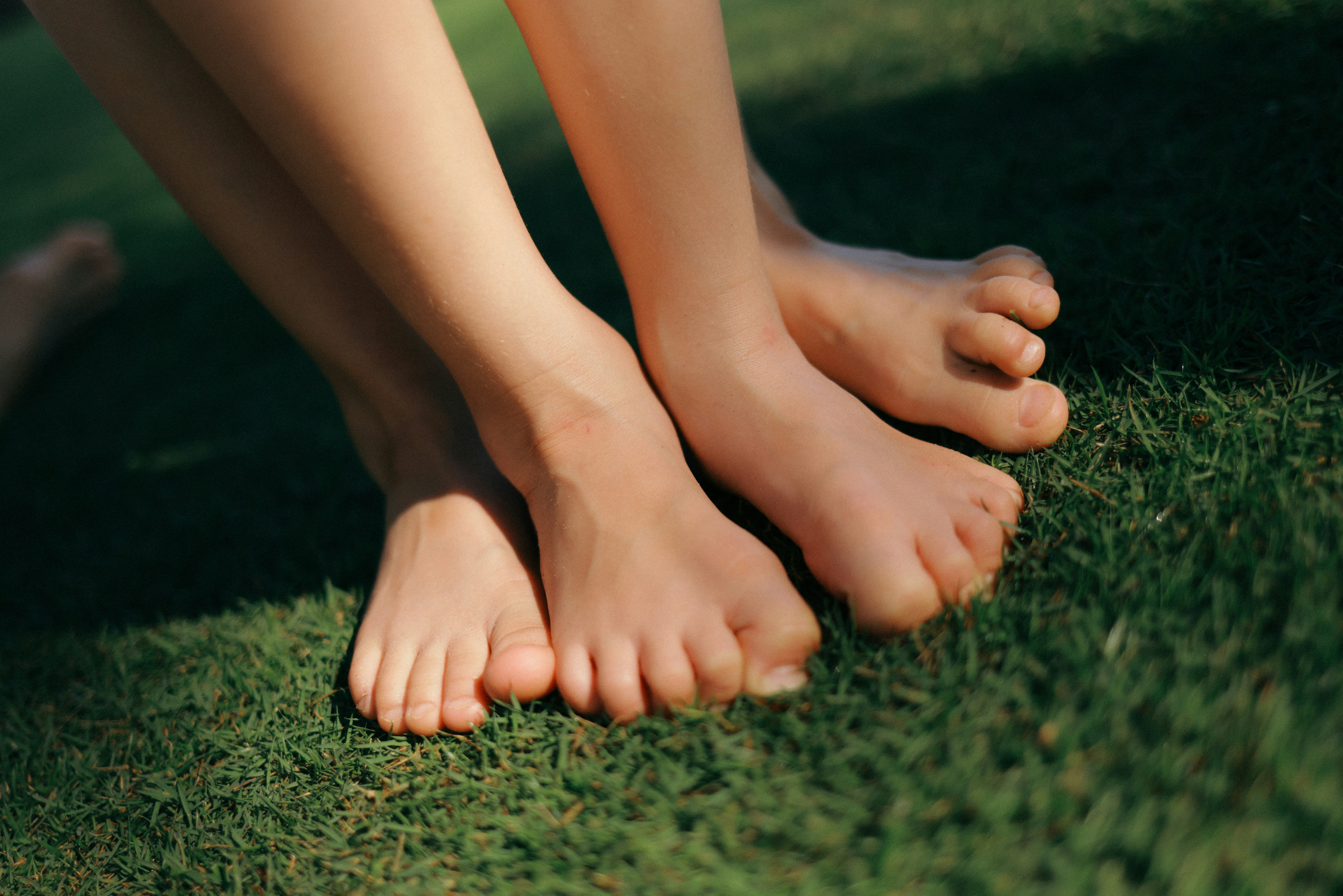 Barefoot Playground: A Pair of Feet Resting on Sunlit Grass