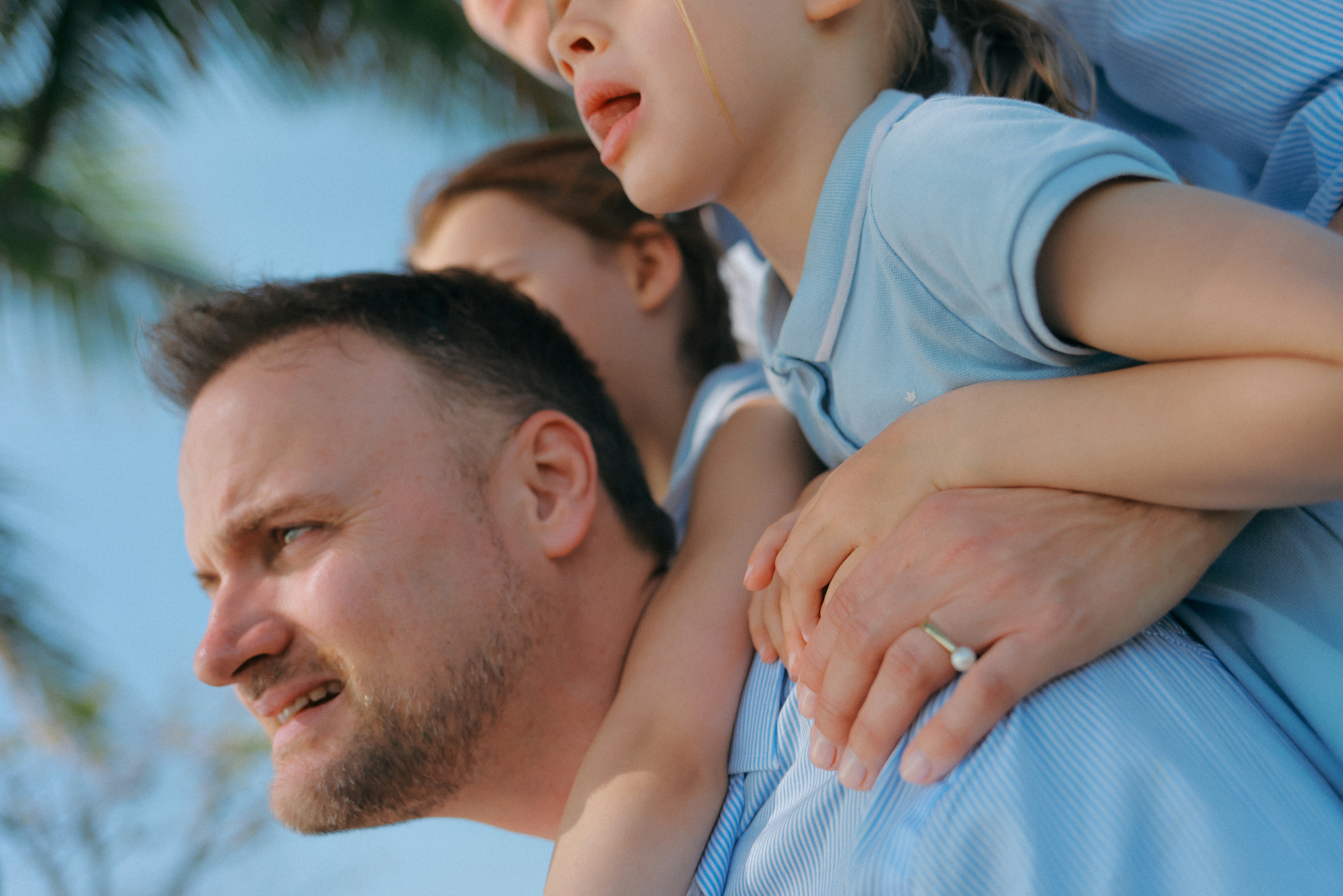 Family Moment Under Bright Sky: Father Carrying Daughter on Shoulders