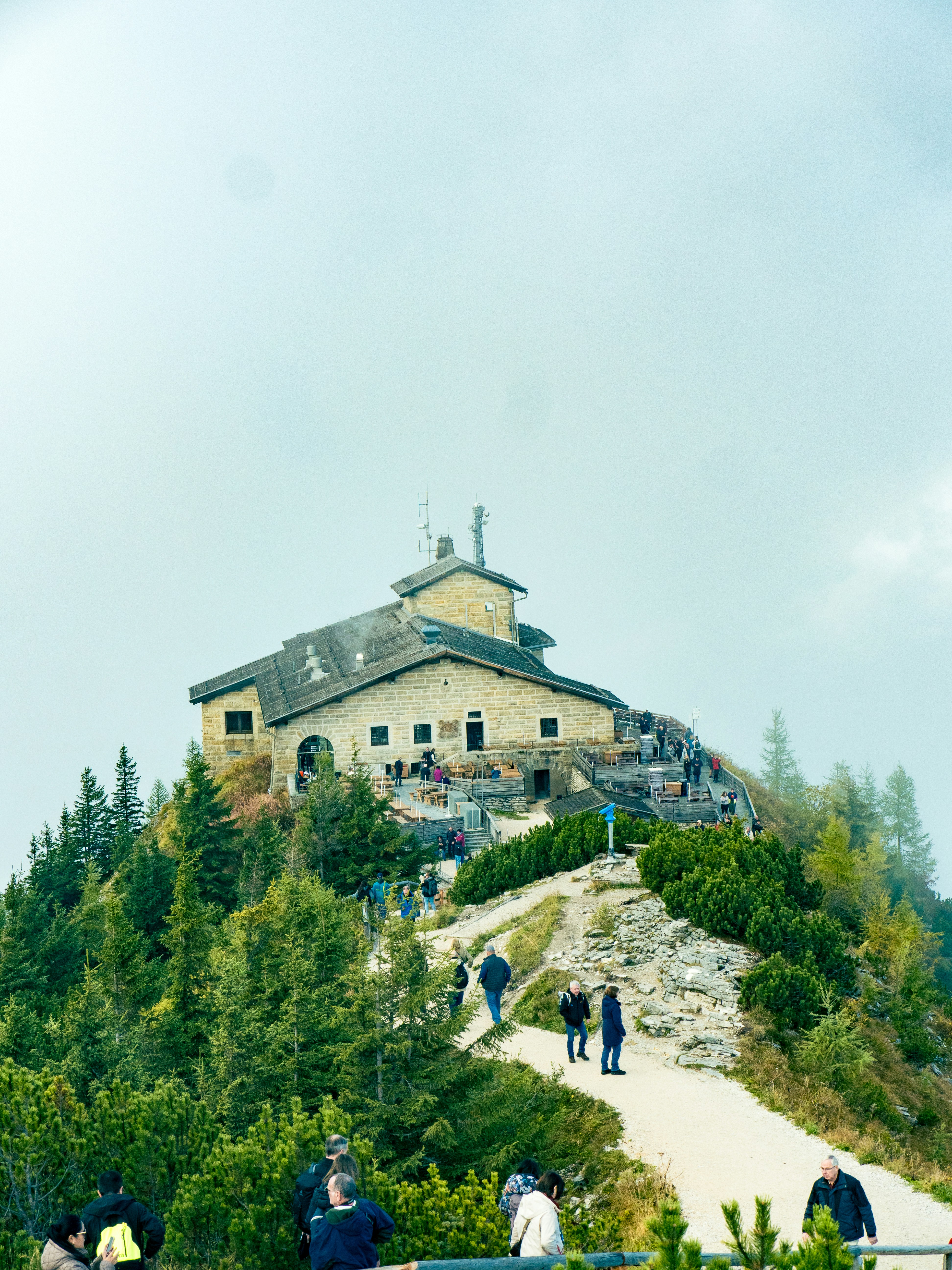 Stone hut on a windswept summit, trail-worn visitors tracing a path to the overlook