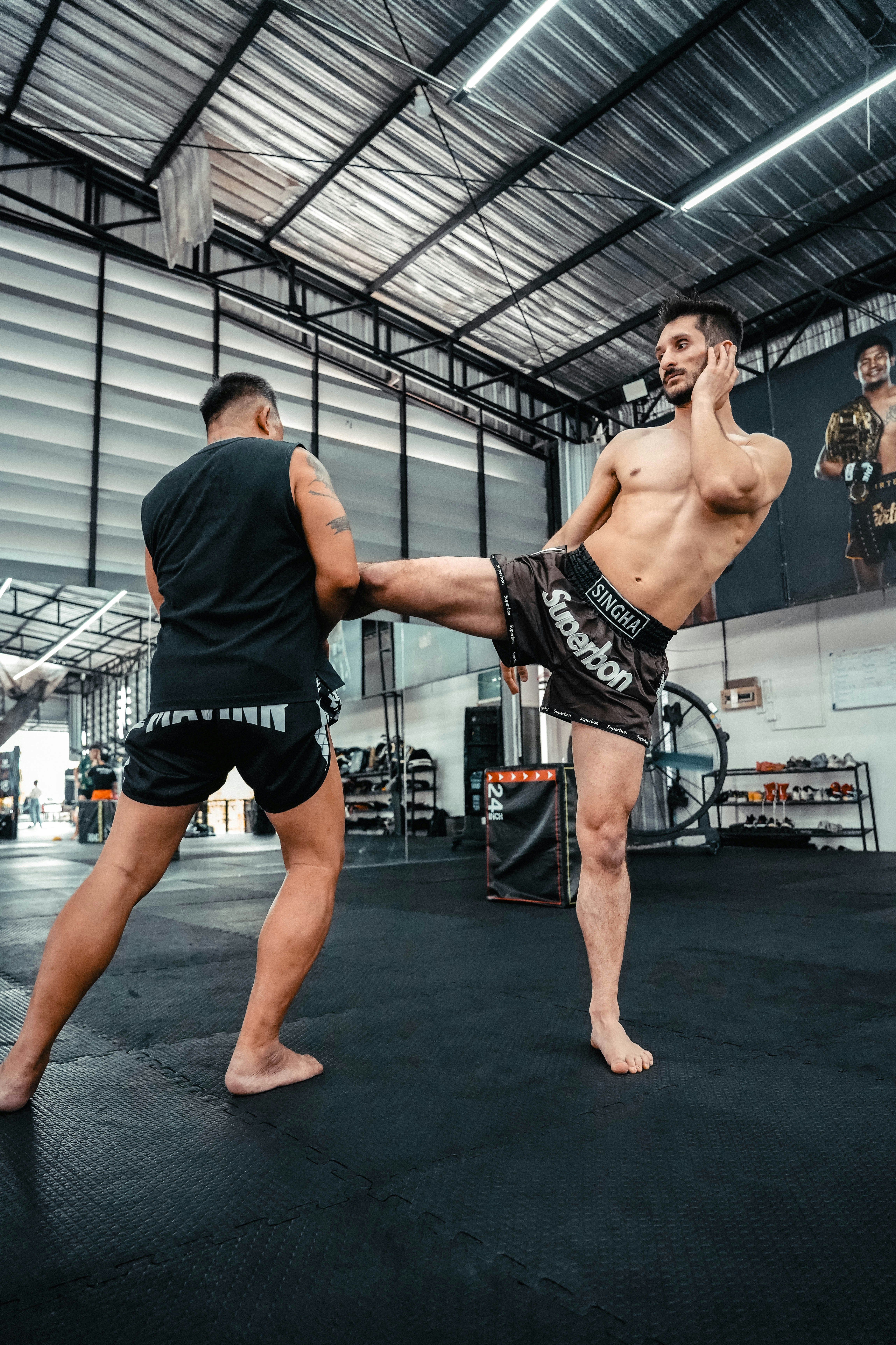Two men practicing muay thai kickboxing in a gym.