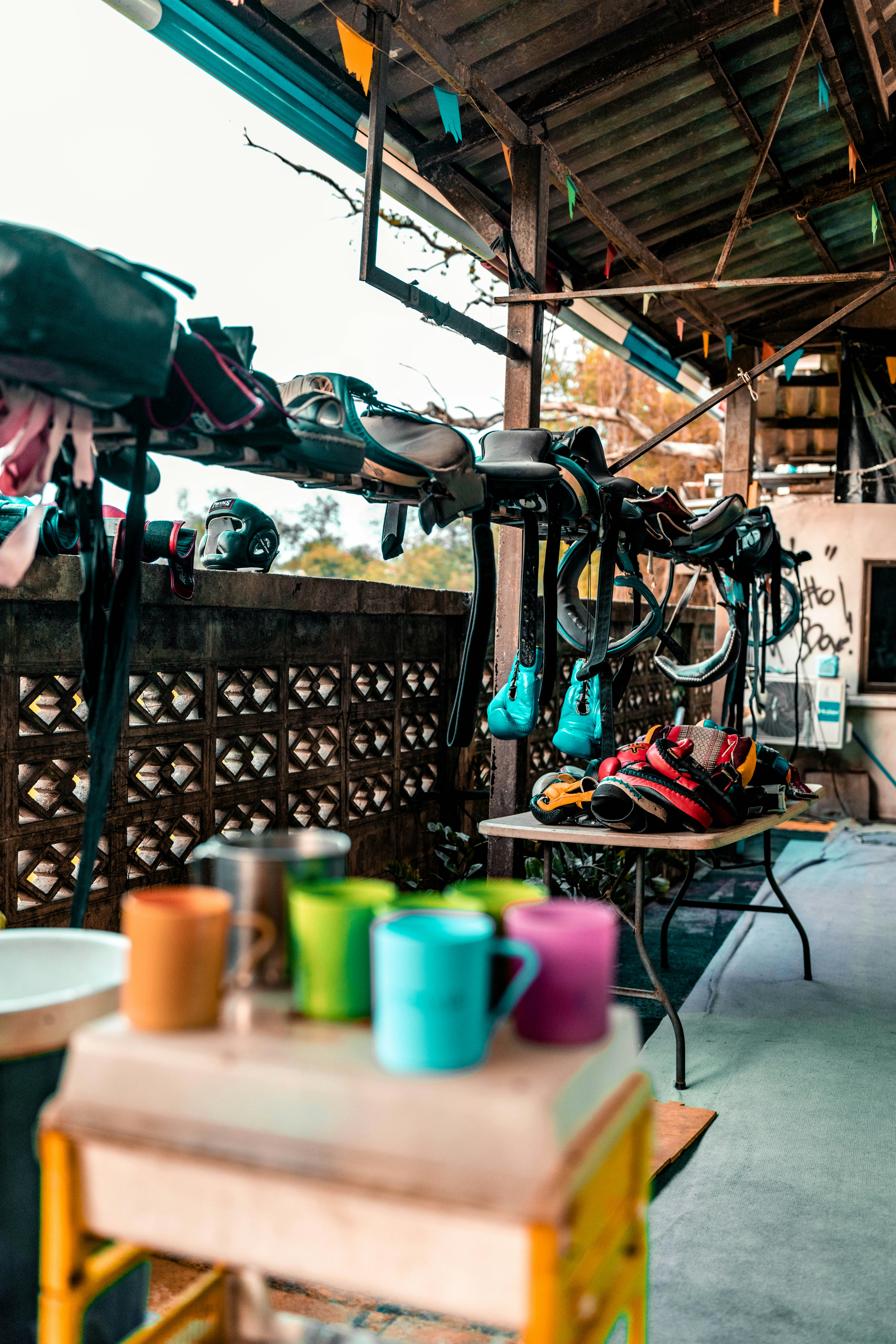 Colorful Mugs and Cycling Gear under a Shaded Outdoor Shelter