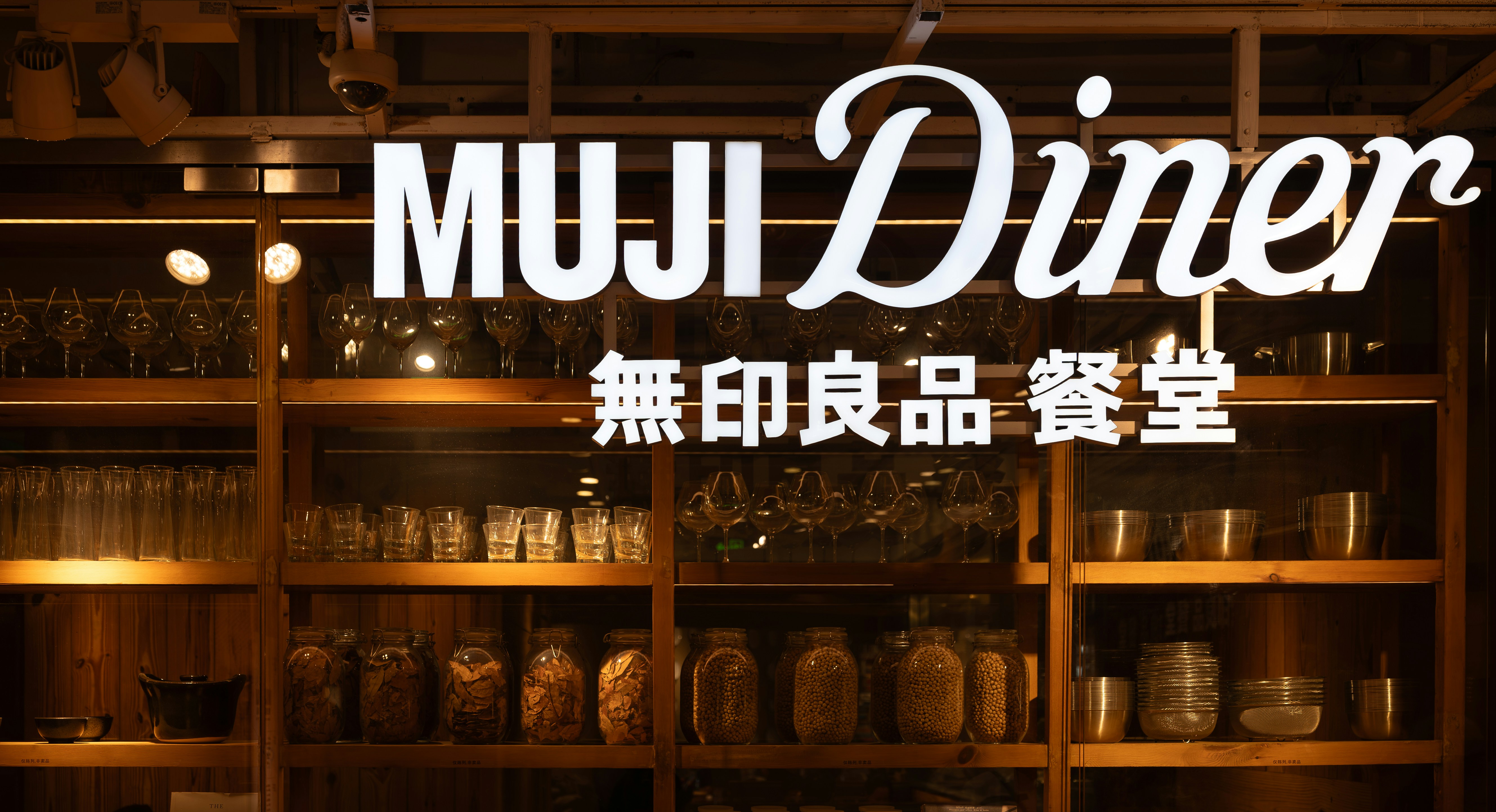 Shopfront glow: MUJI Diner signage over warm pantry shelves