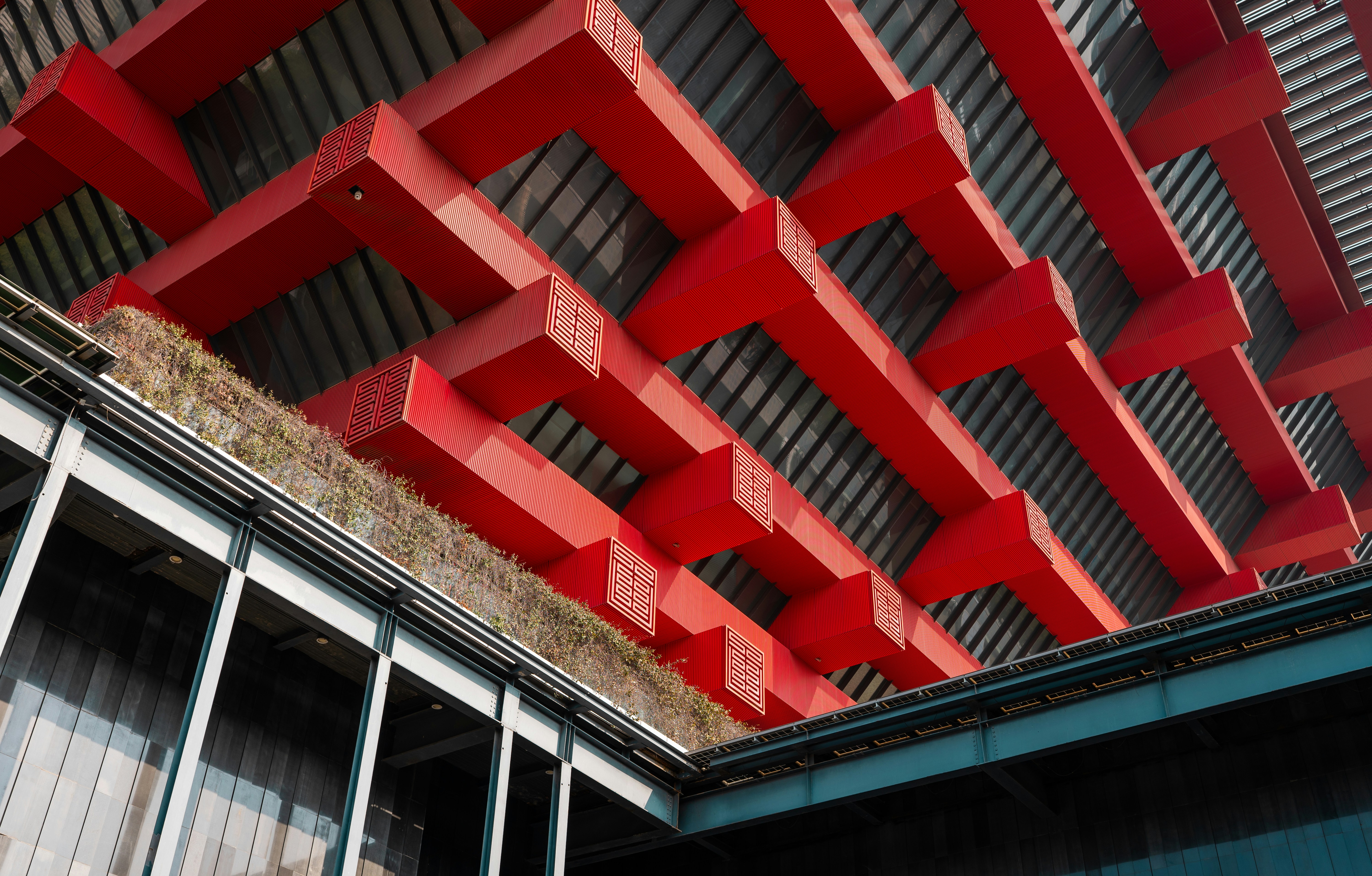 Red Structural Echoes: Geometric Overhangs Above a Glass Facade