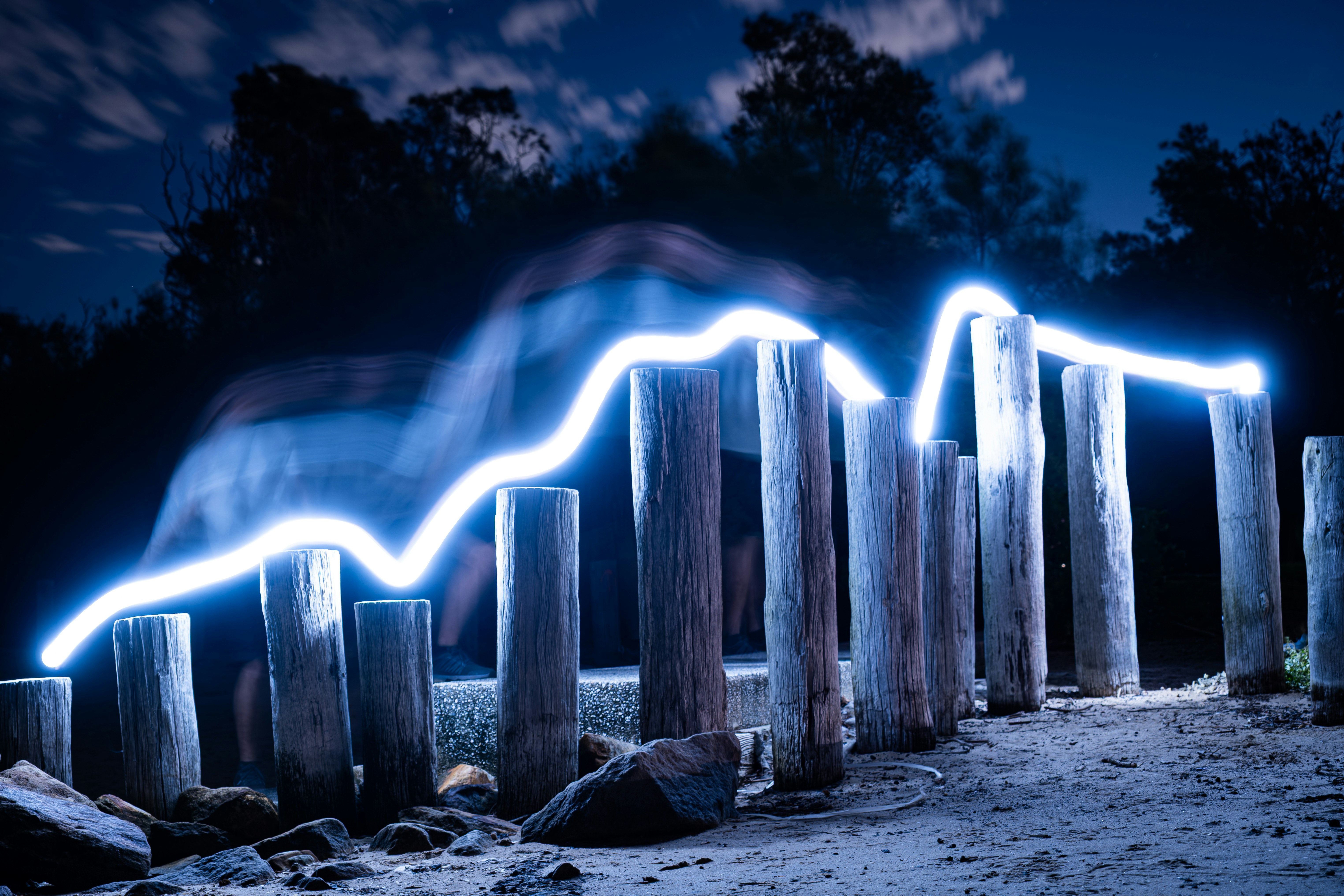 Neon Serpentine Trail: Light Painting Across Weathered Posts