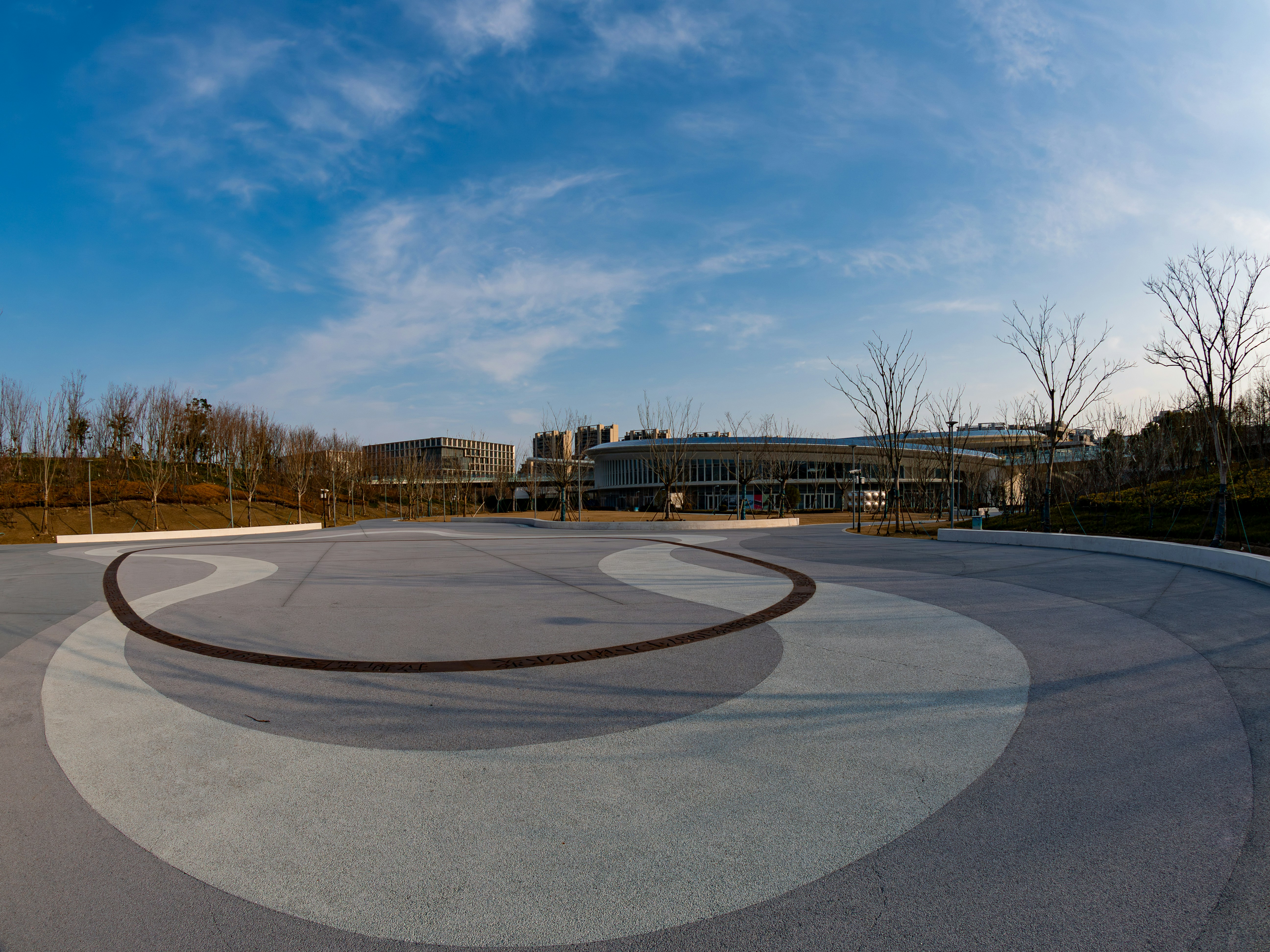 Modern building with circular pavement design under blue sky