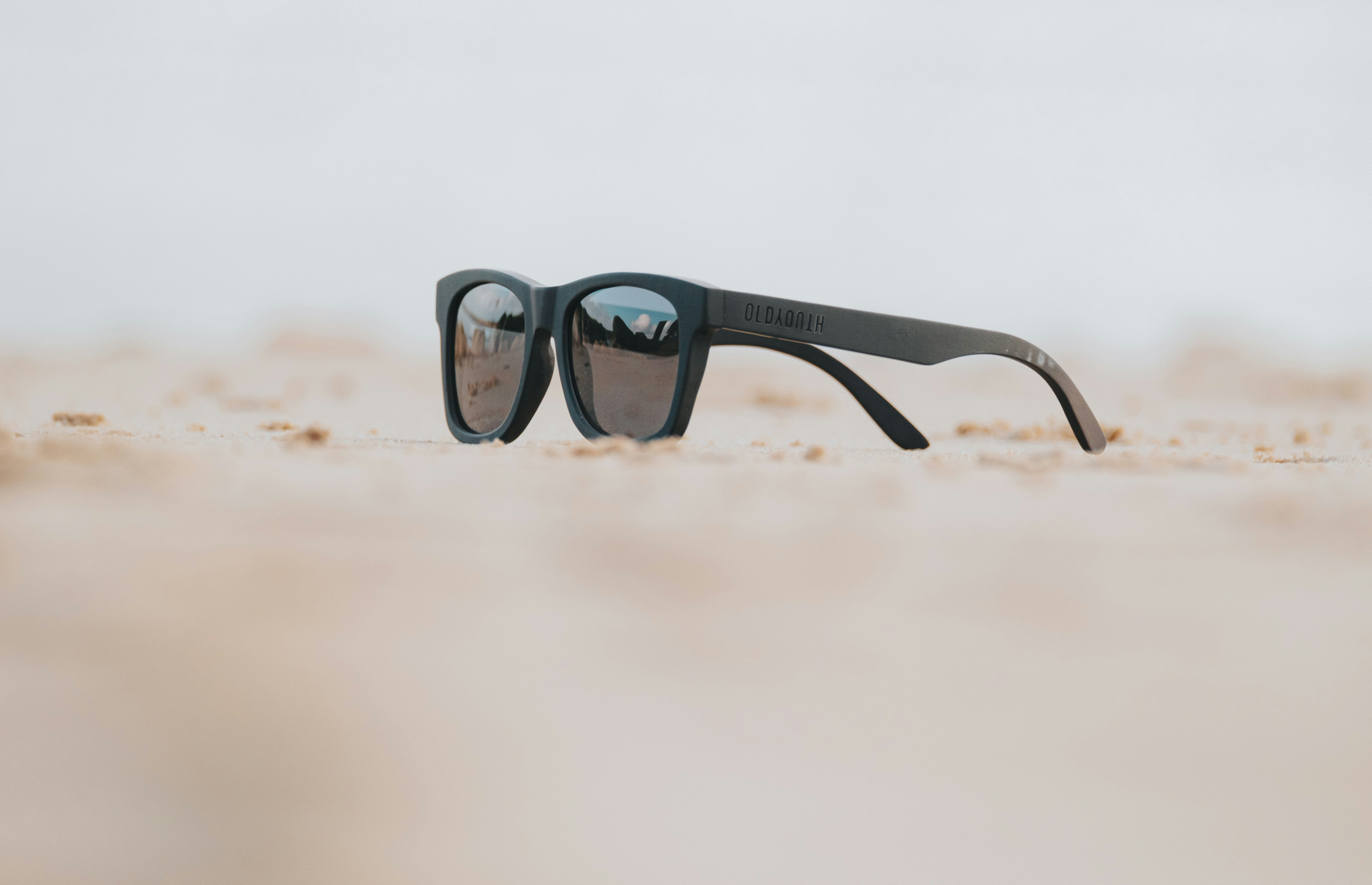 Shaded Gaze on Sand: Sunglasses Resting in Desert Light