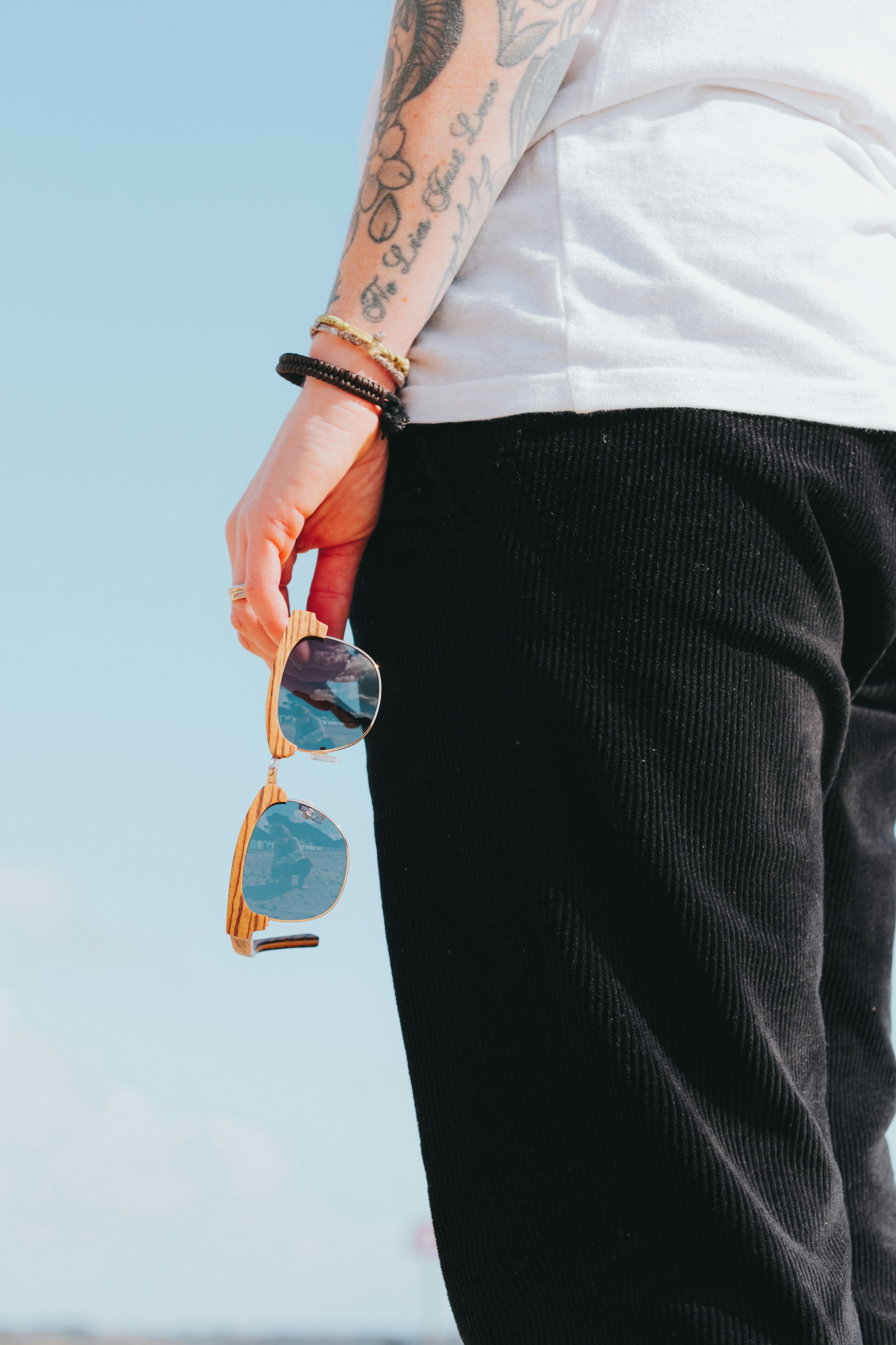 Sunny Horizon Grasp: A Hand Displaying Sunglasses at Beachside