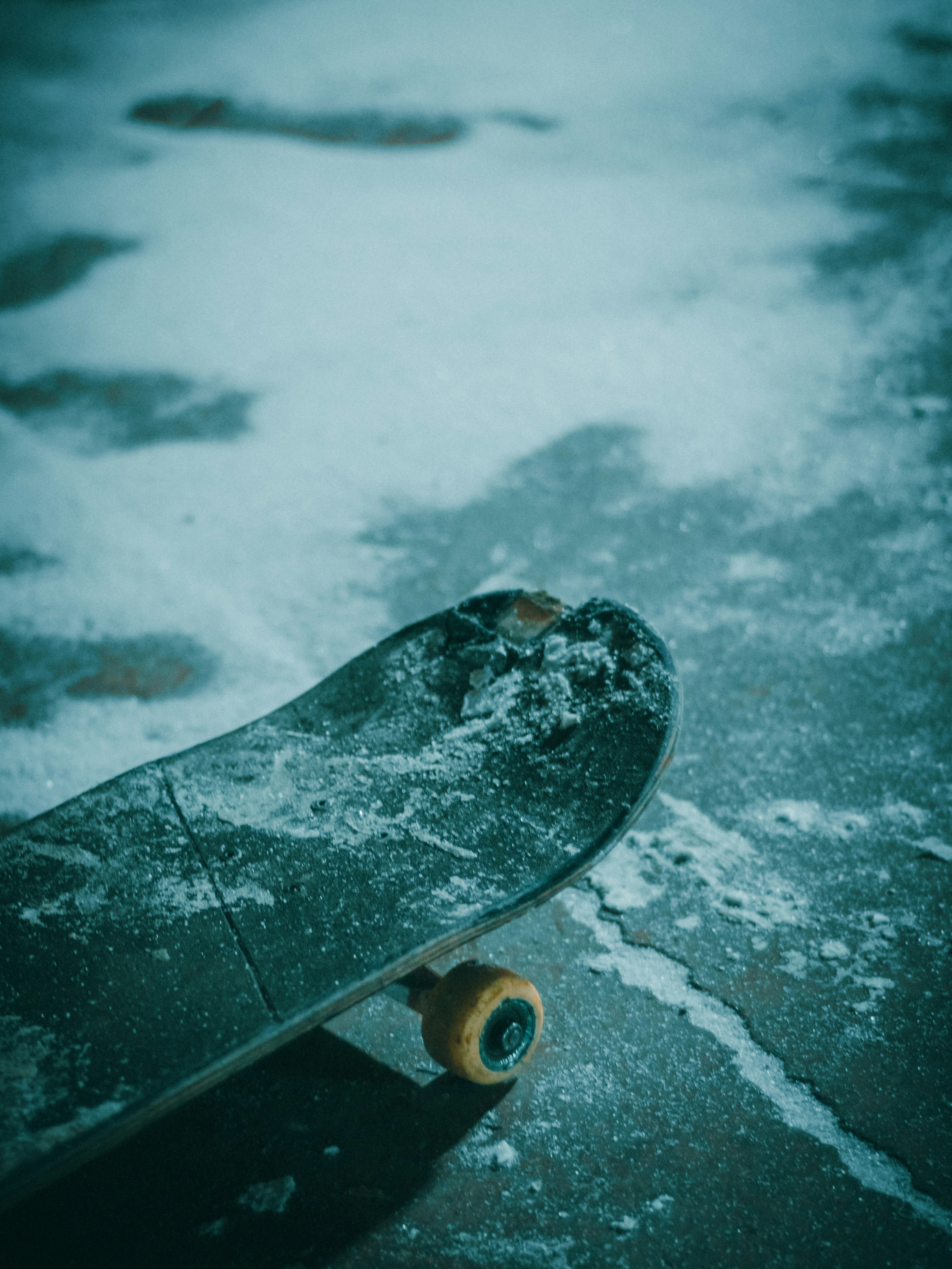 Frayed Board and Frost: a Skateboard Resting on Iced Pavement