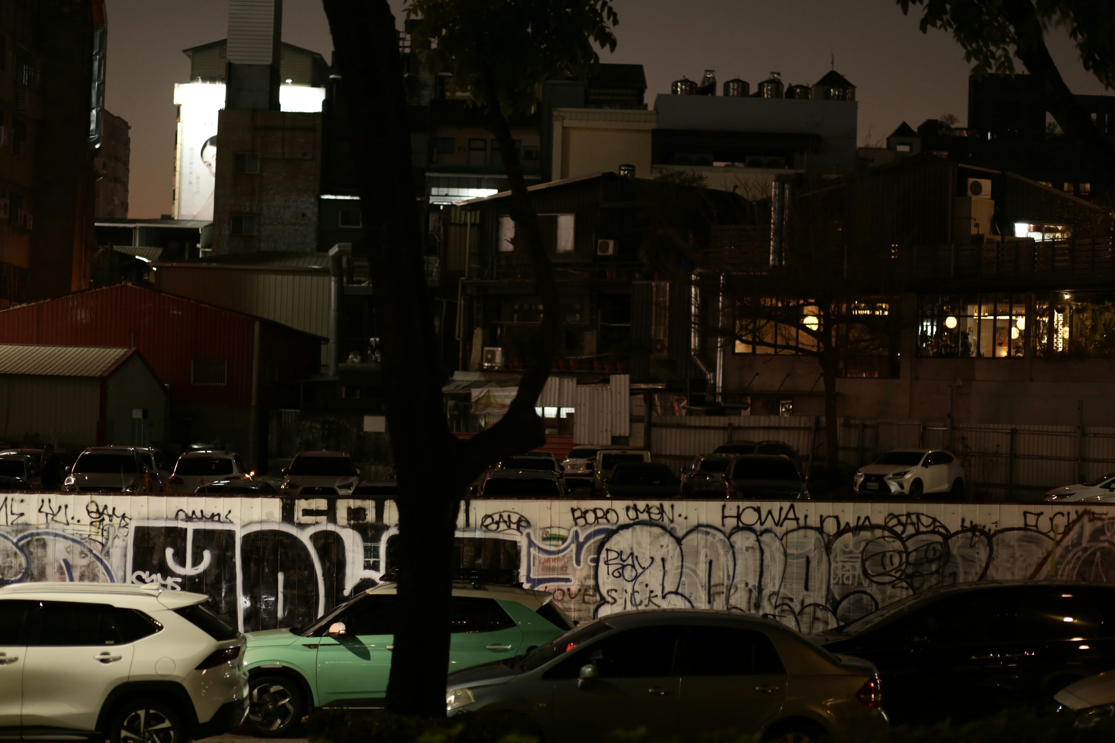 Night Street Portrait: Graffiti Terrace Behind a Quiet Line of Cars