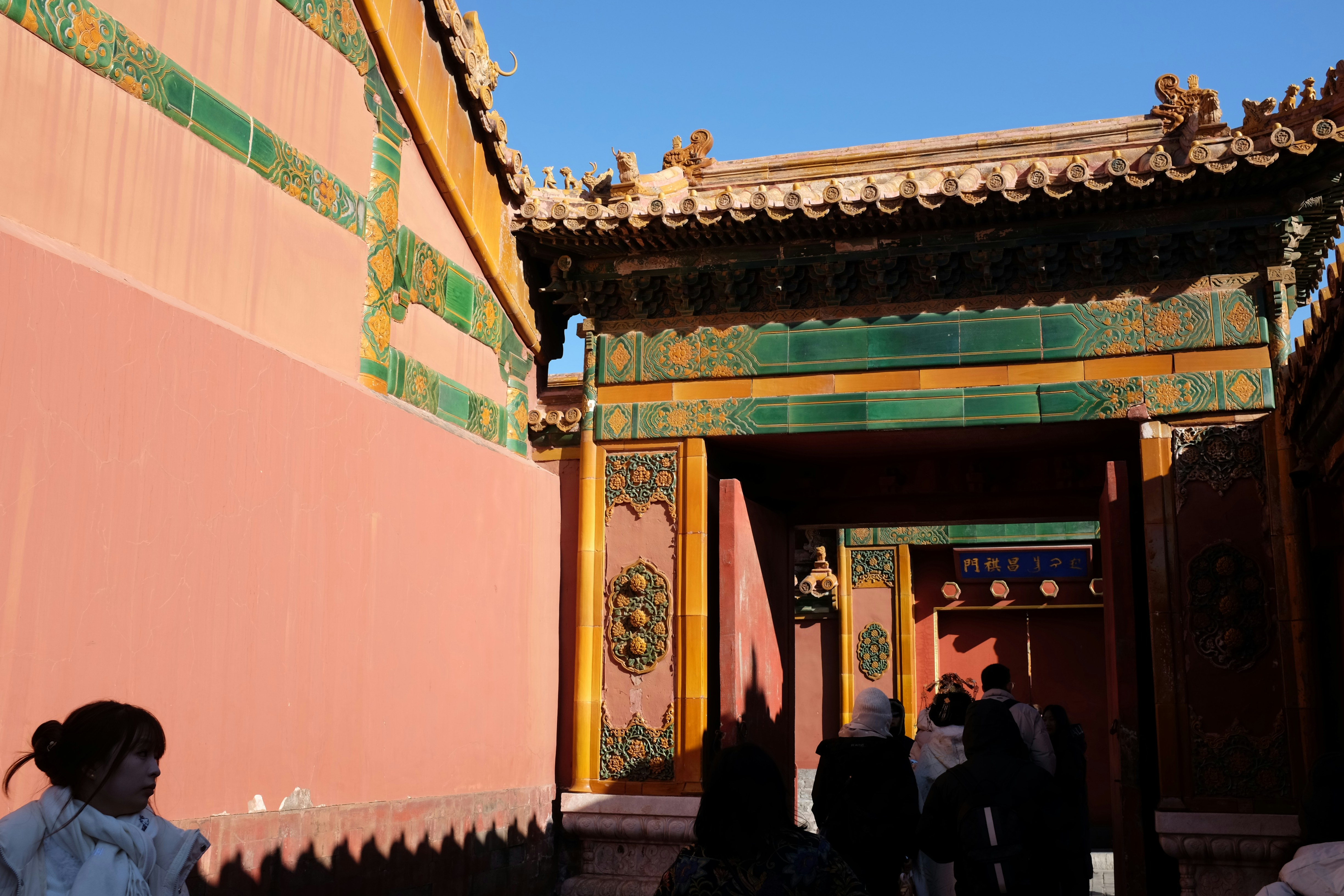 Sunlit Threshold: People Entering an Ornate Gate at Dusk