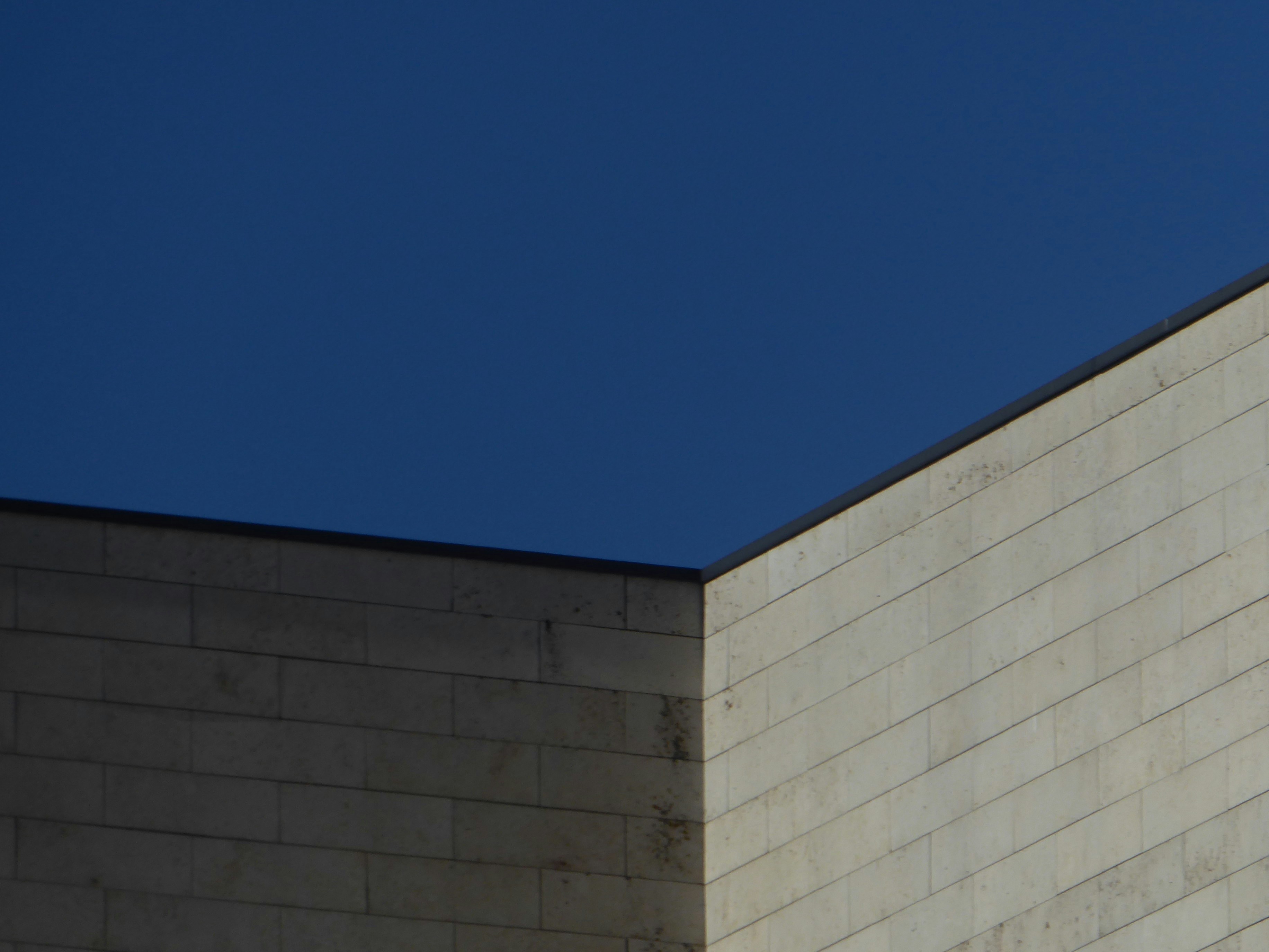 A stark architectural composition with blue sky and concrete walls.
