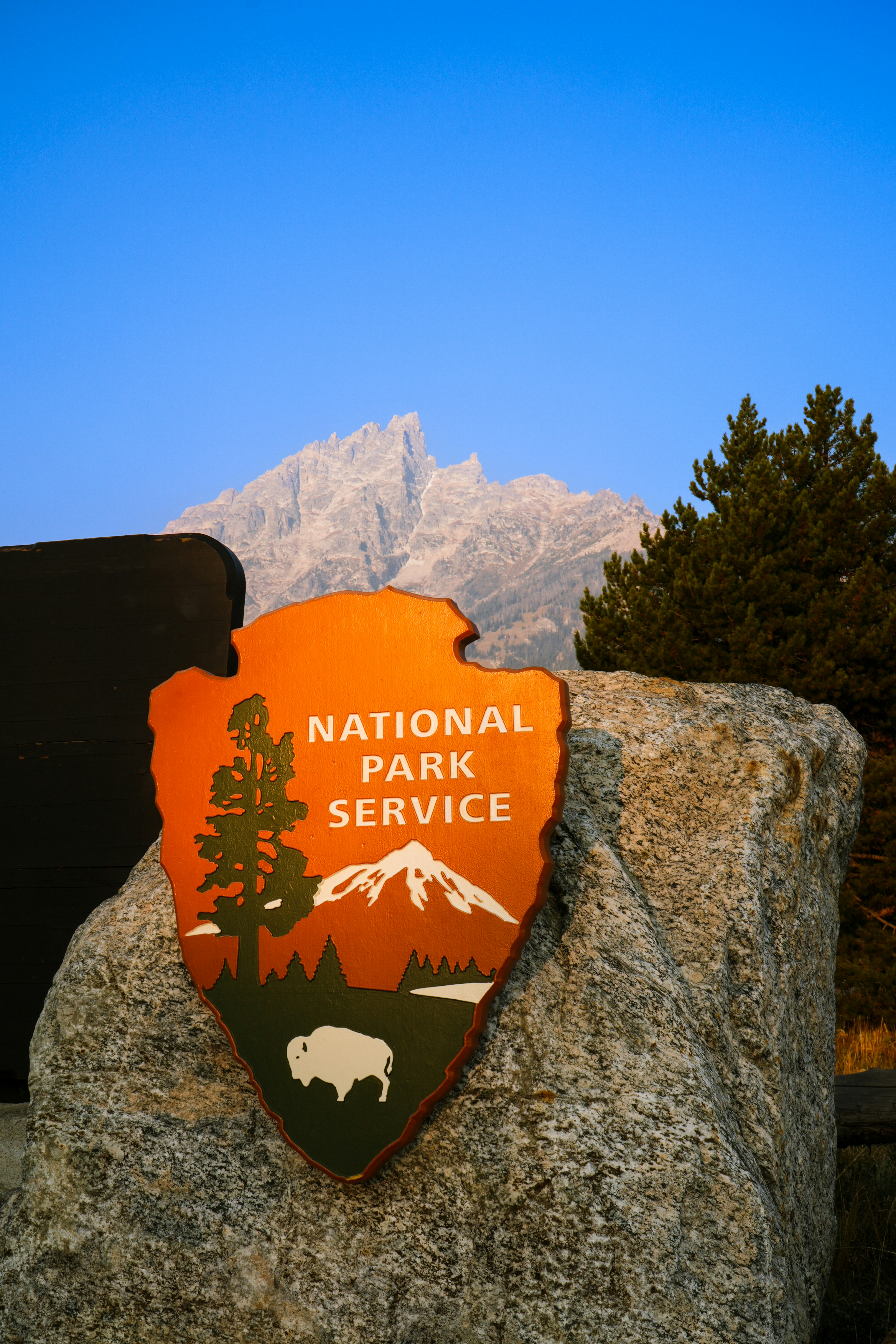 Orange National Park Sign Framed by Granite and Pines Under a Blue Sky
