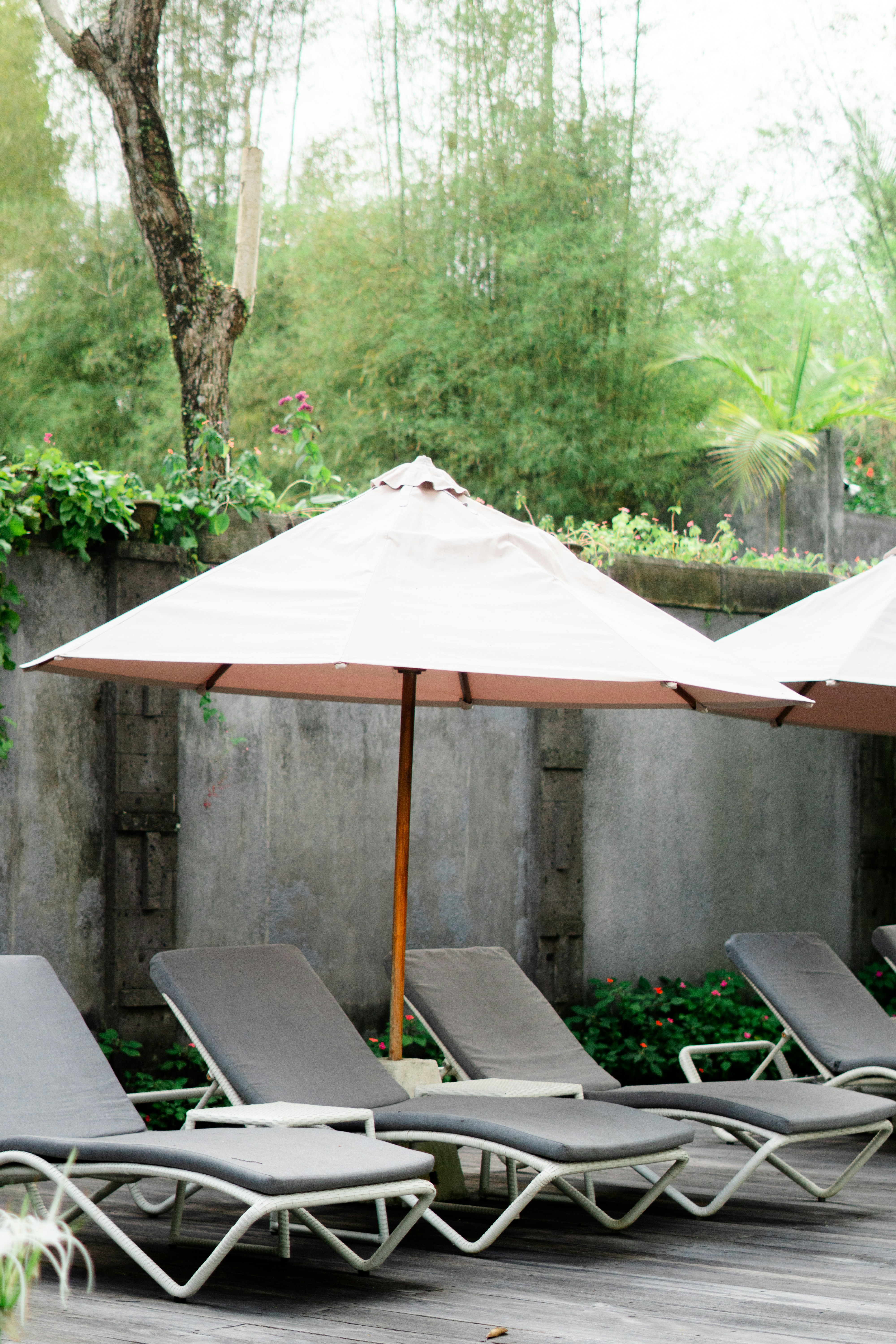Sunlit loungers under a pastel parasol in a serene courtyard