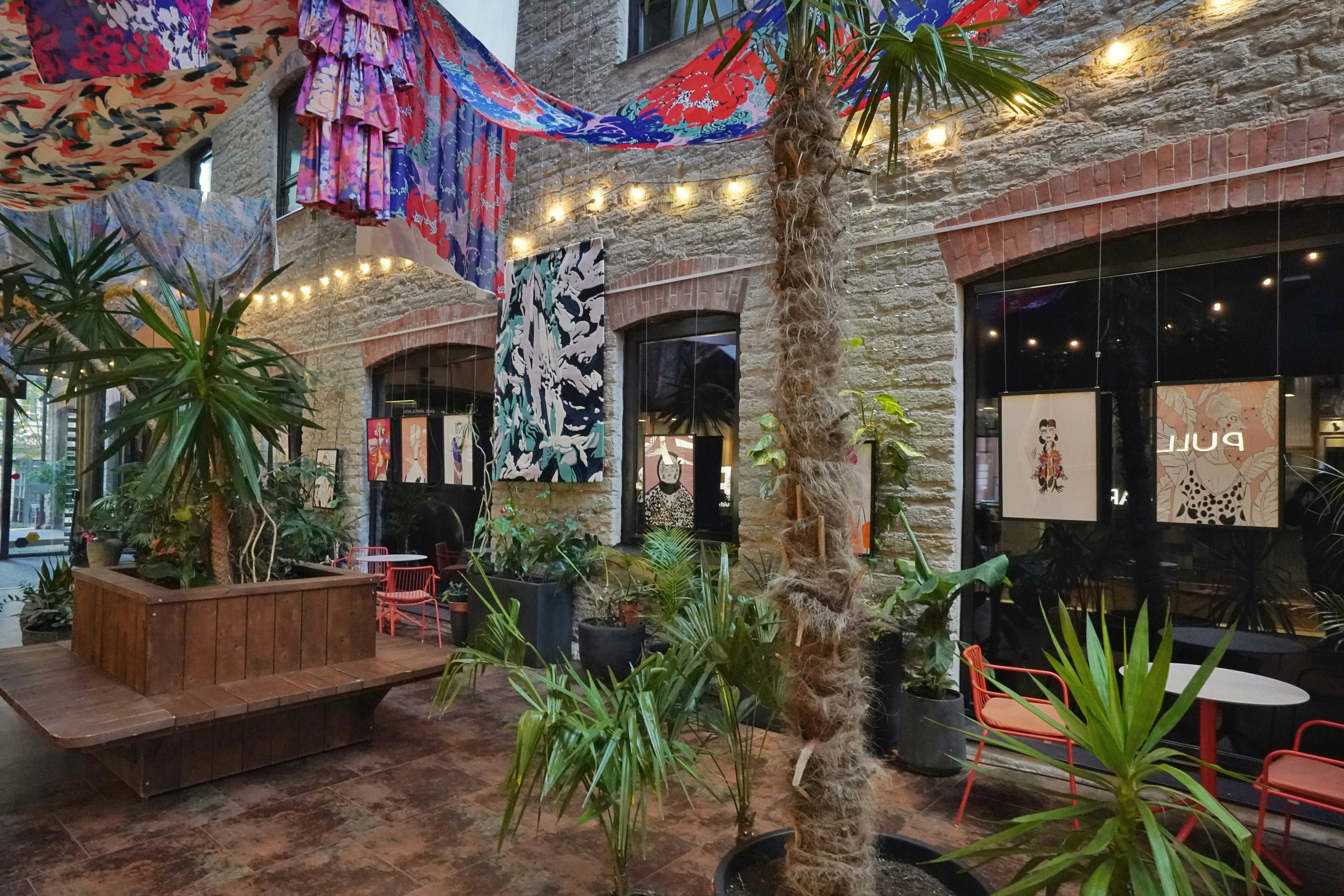 Colorful courtyard cafe under textile canopies with tropical plants