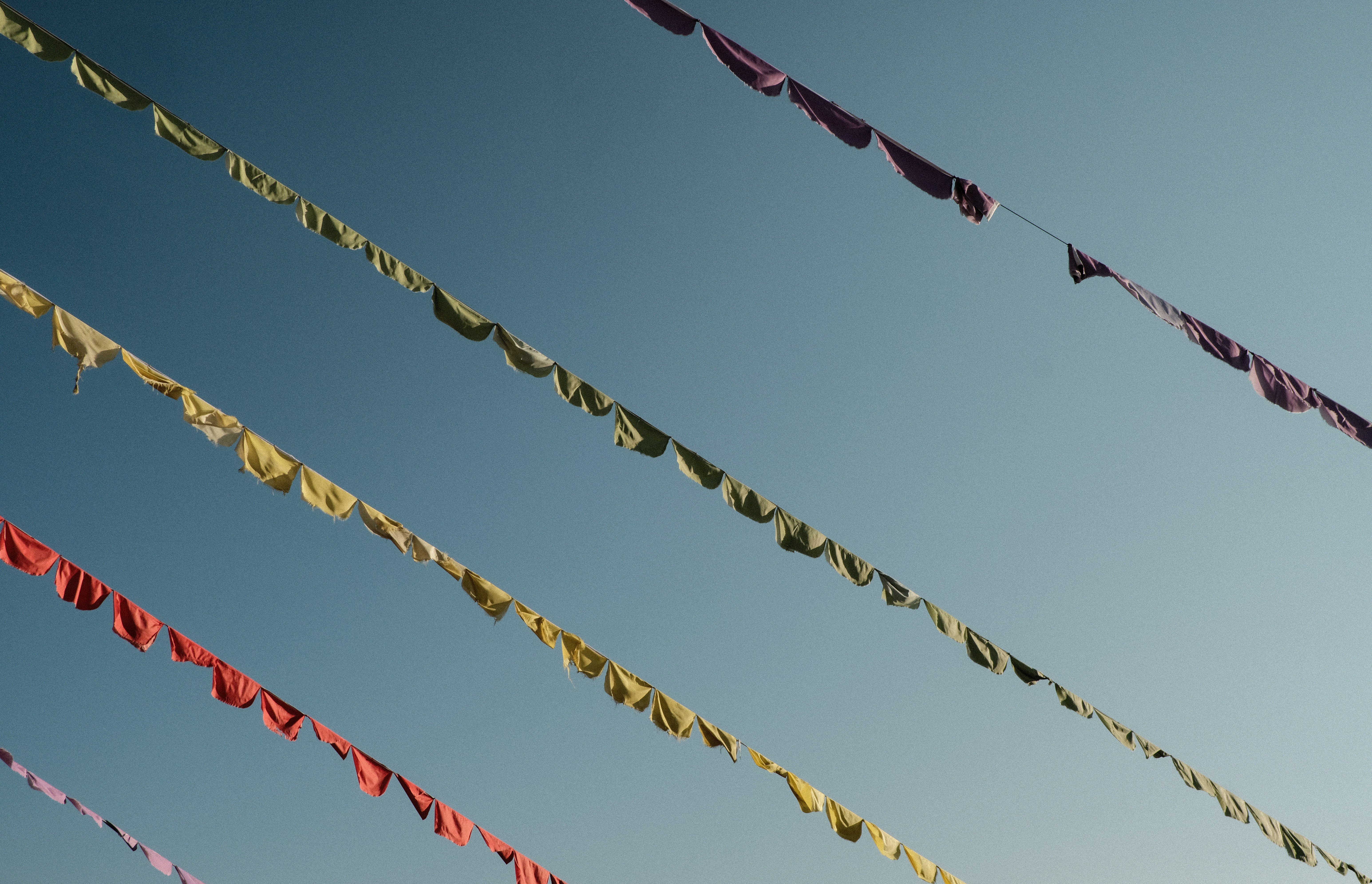Colorful flags strung across a clear blue sky