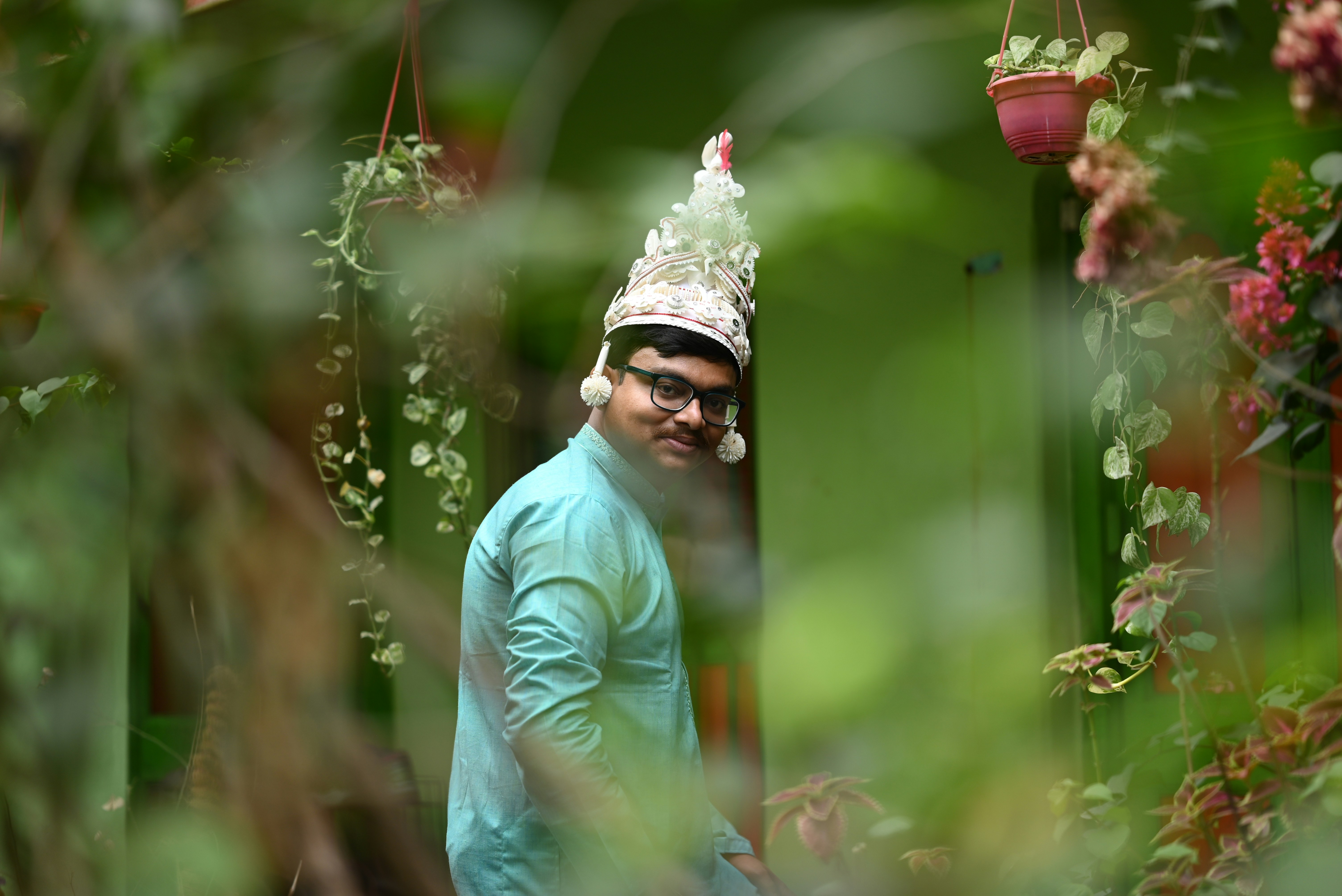 Portrait in a Green Garden: A Performer in Teal Amid Hanging Foliage