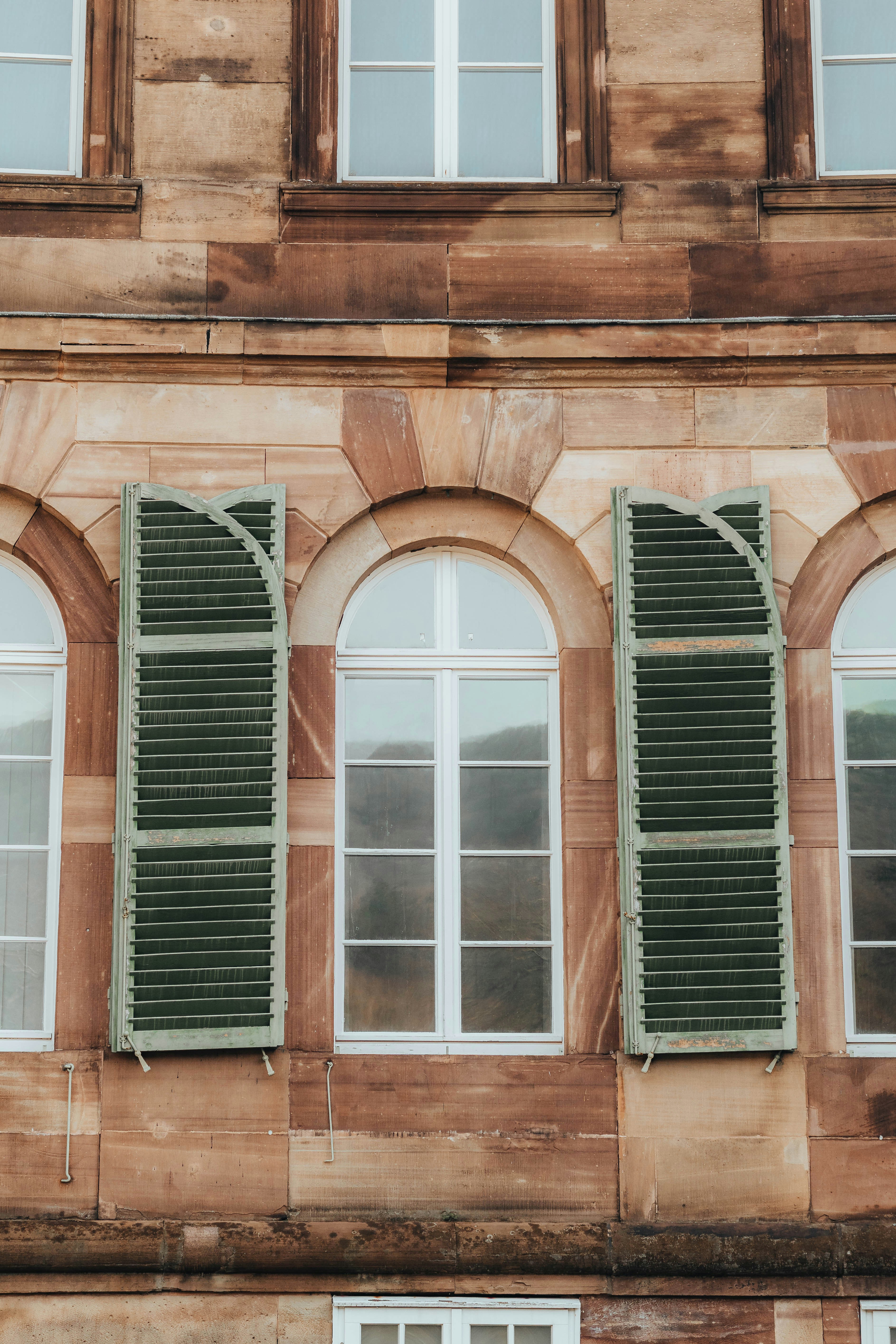 Open Green Shutters on a Warm Stone Facade