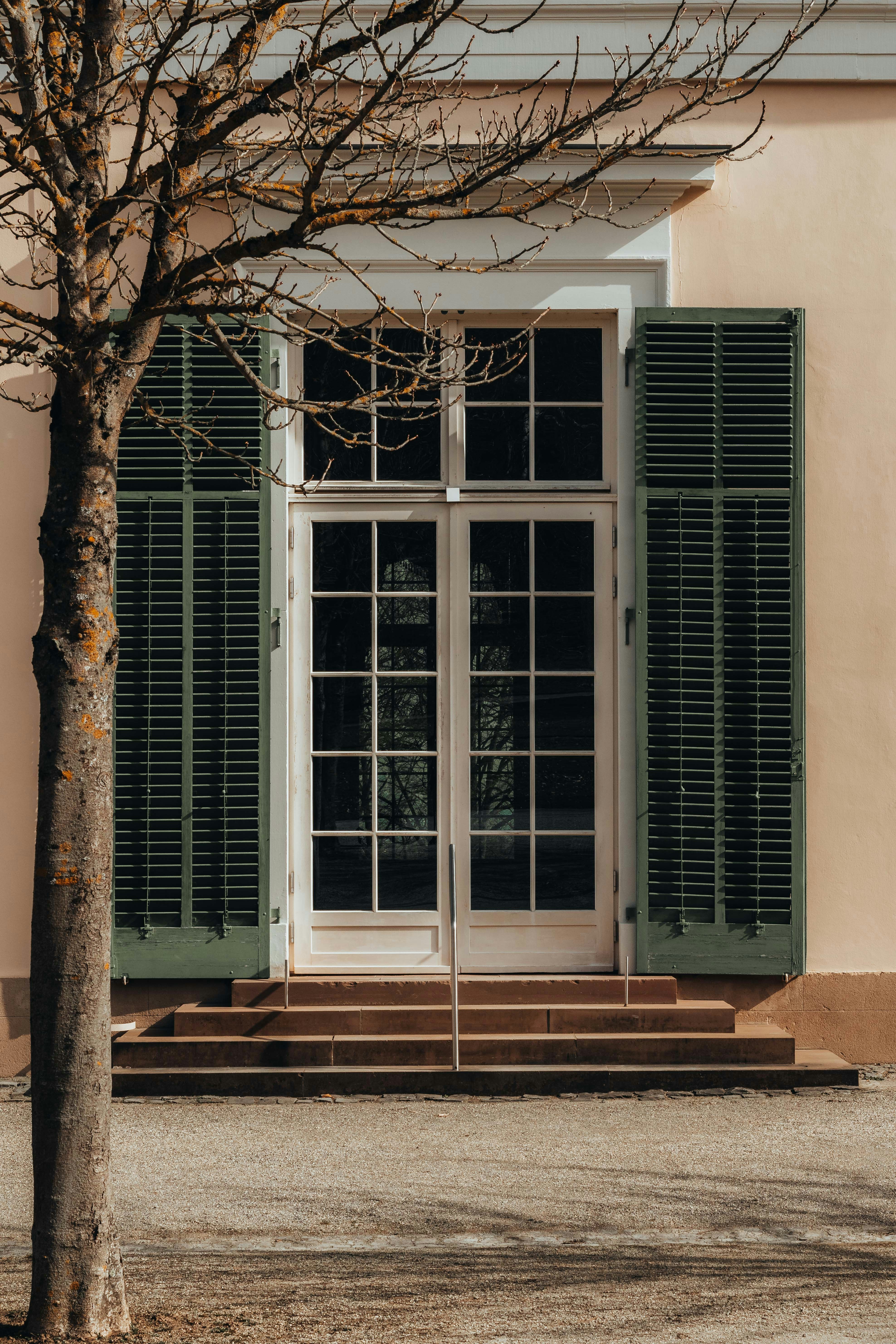 Muted Facade with Green Shutters and Central Doorway