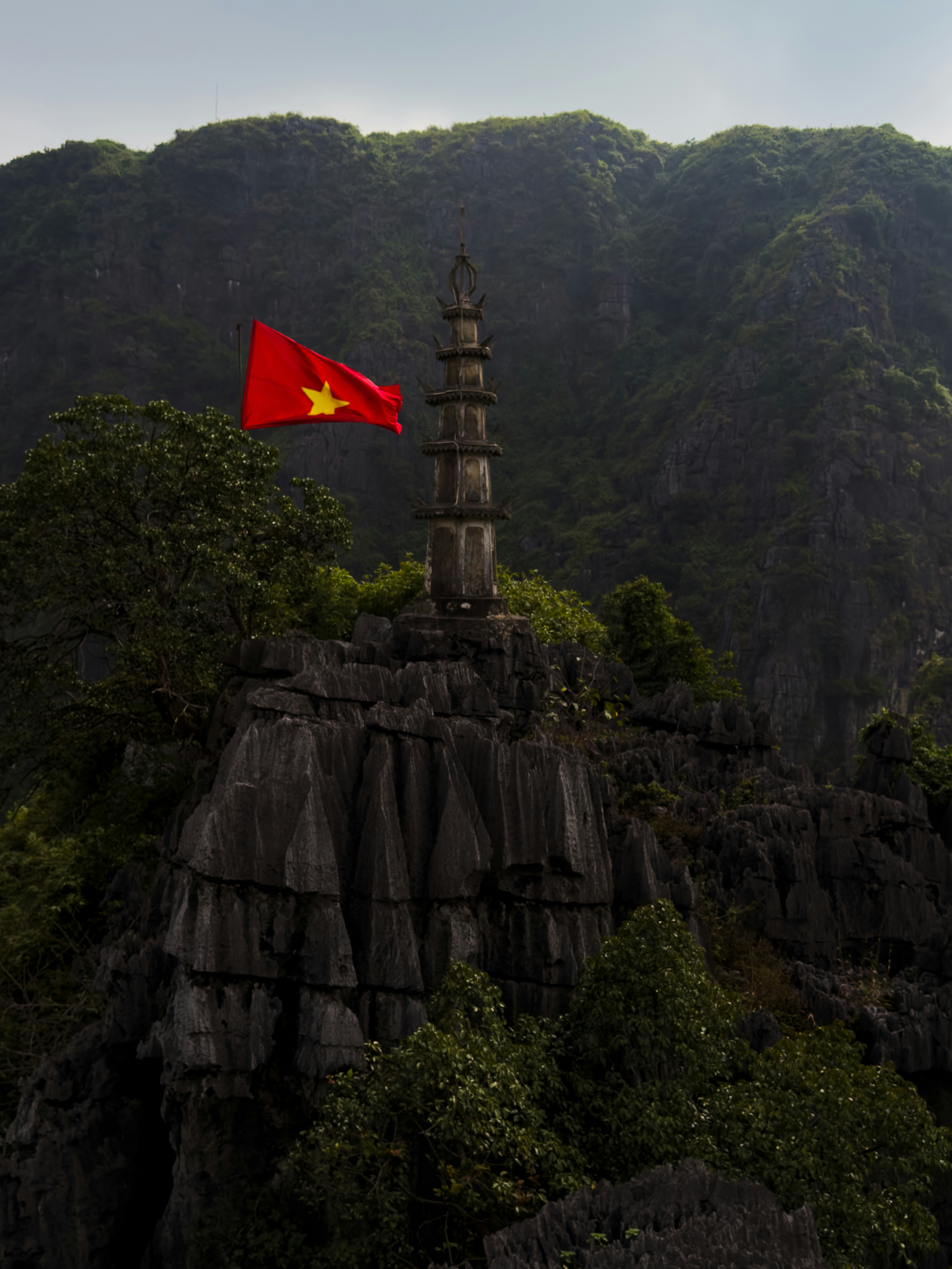 Flag over basalt pinnacle: a Vietnamese memorial tower climbs the cliff