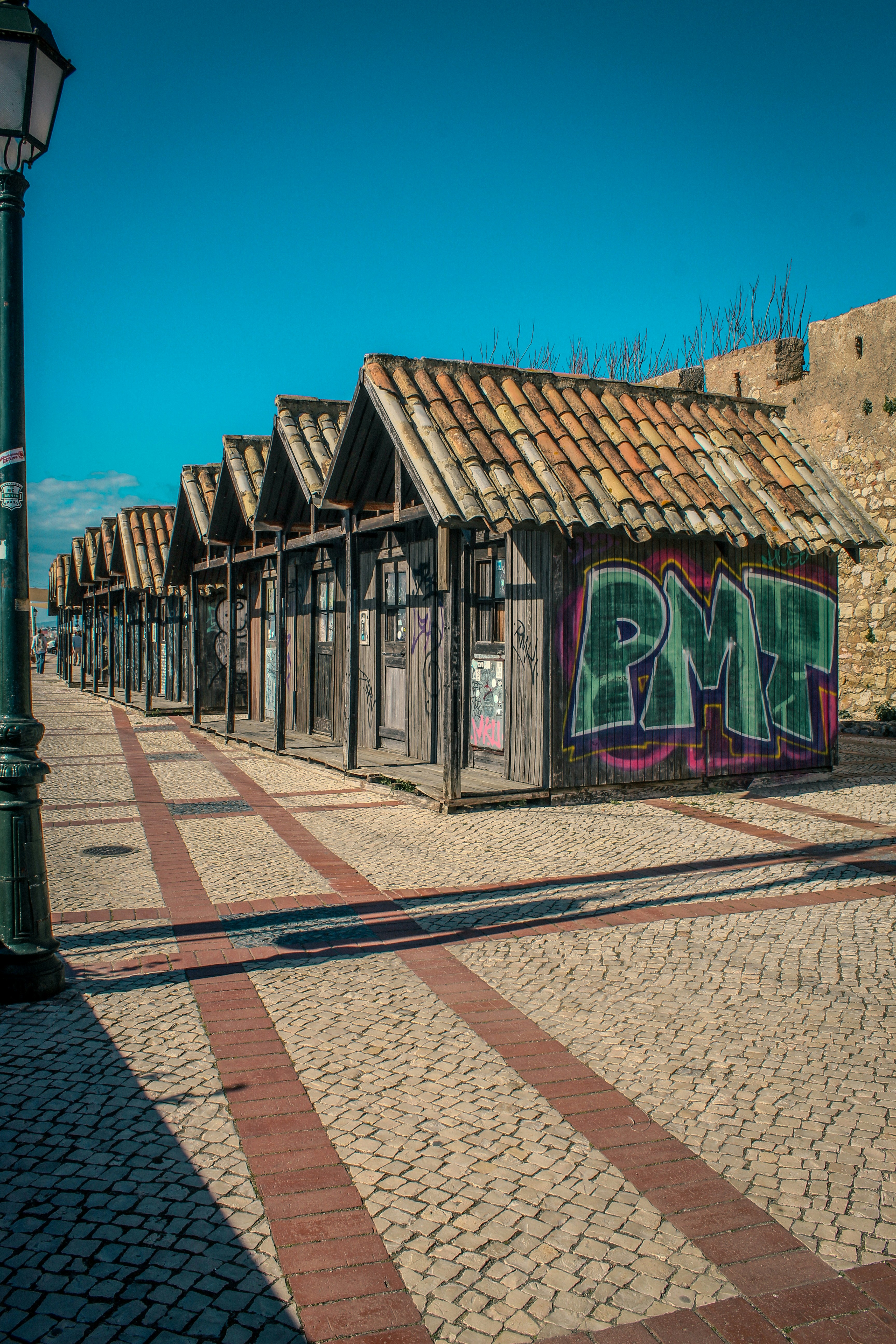 Row of Graffiti-Kissed Market Stalls under a Blue Skiescape