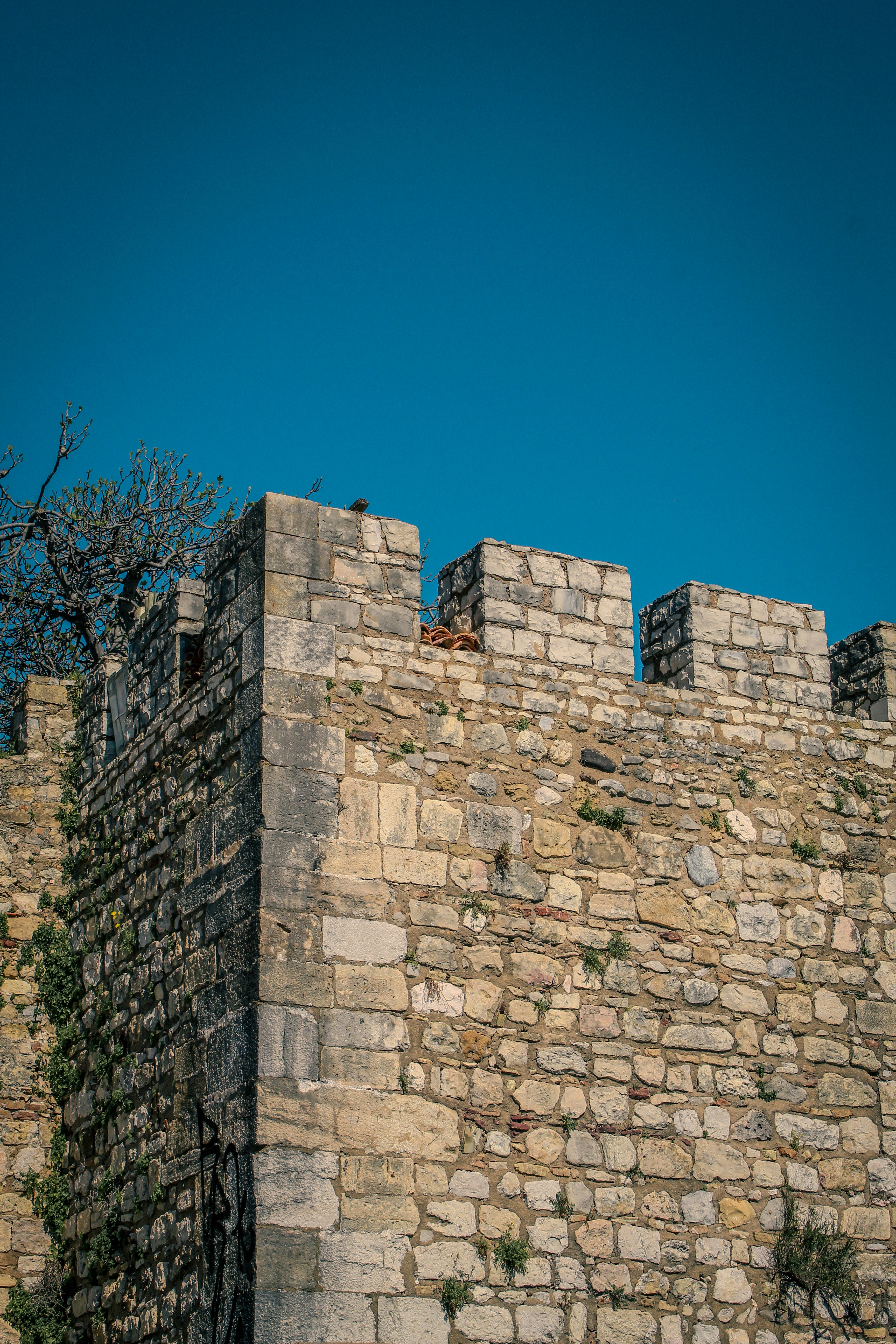 Stone castle wall with crenellations against blue sky