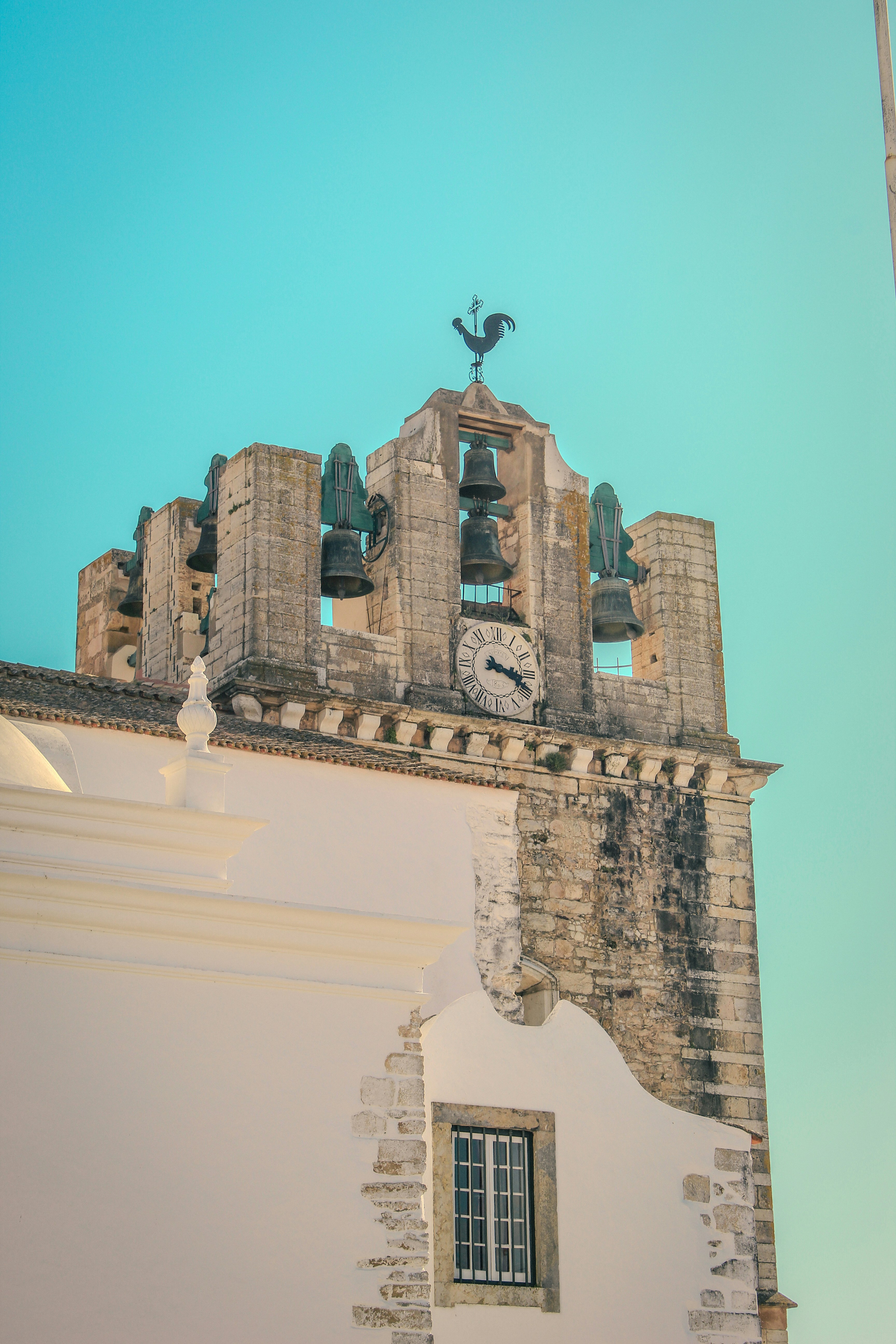 Tower of Bells: A Sunlit Facade with Weathered Stone and Cerulean Sky