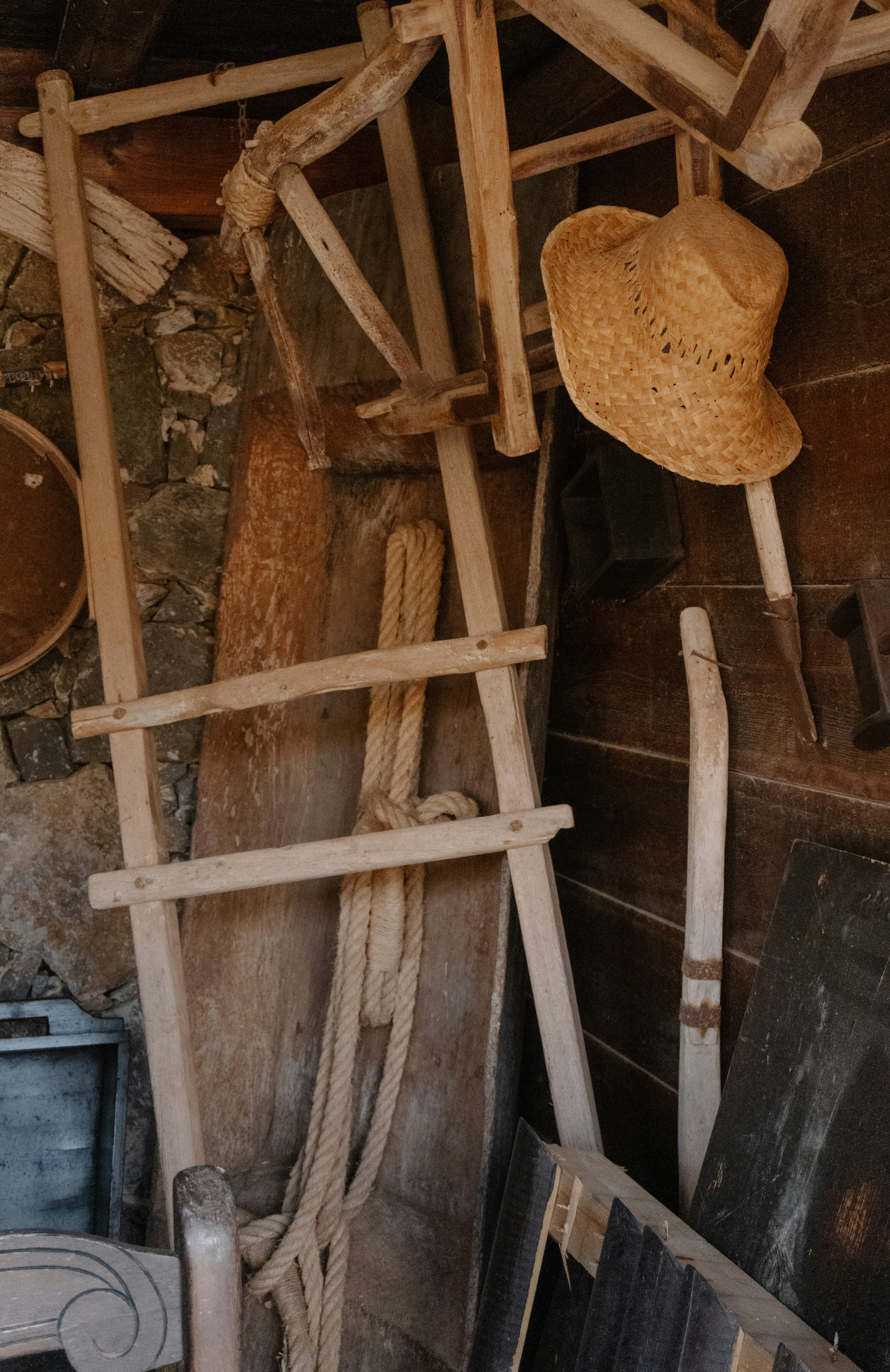 Straw hat hanging above rustic wooden tools and structures.