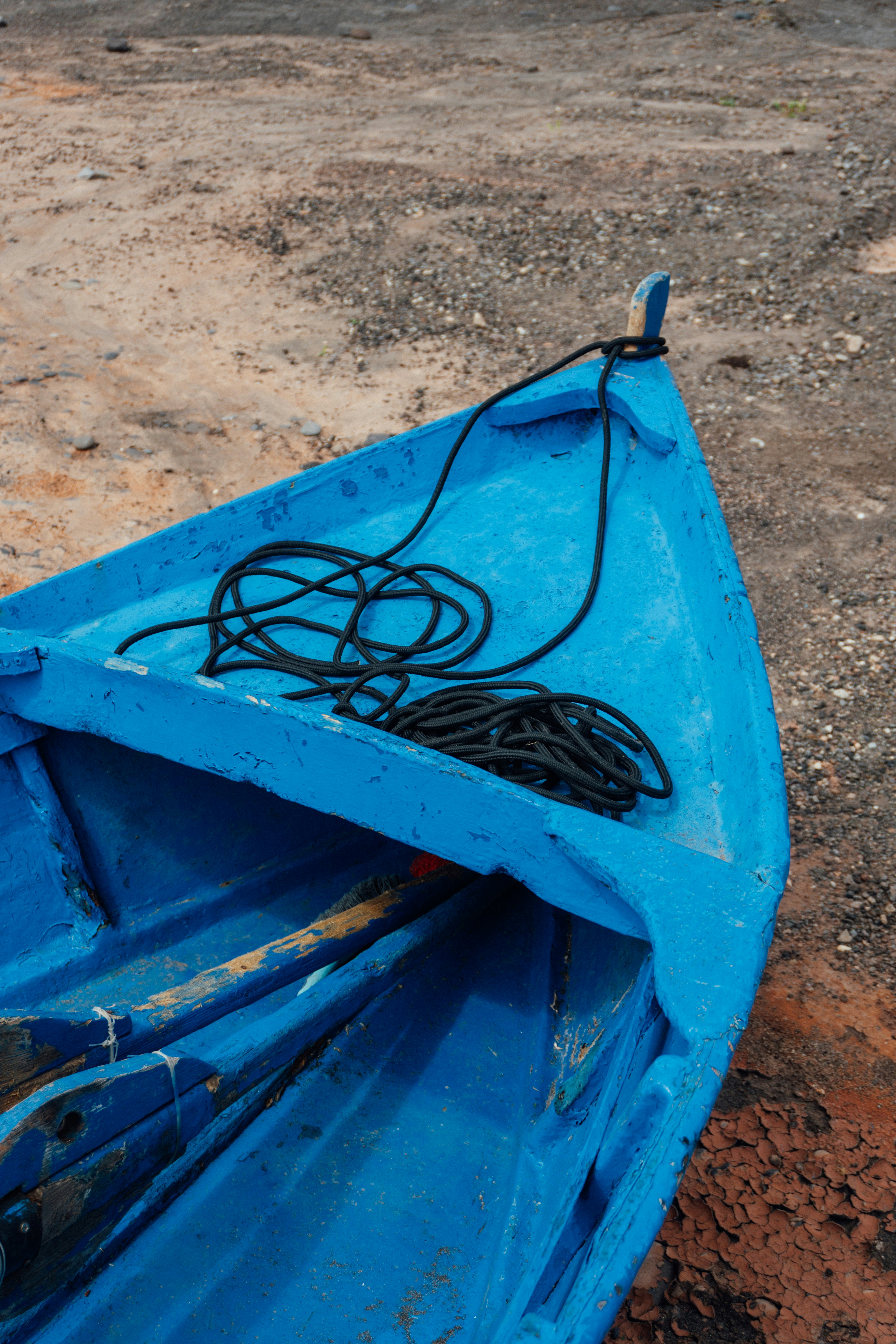 Azure Rowboat Resting on Pebbled Shore