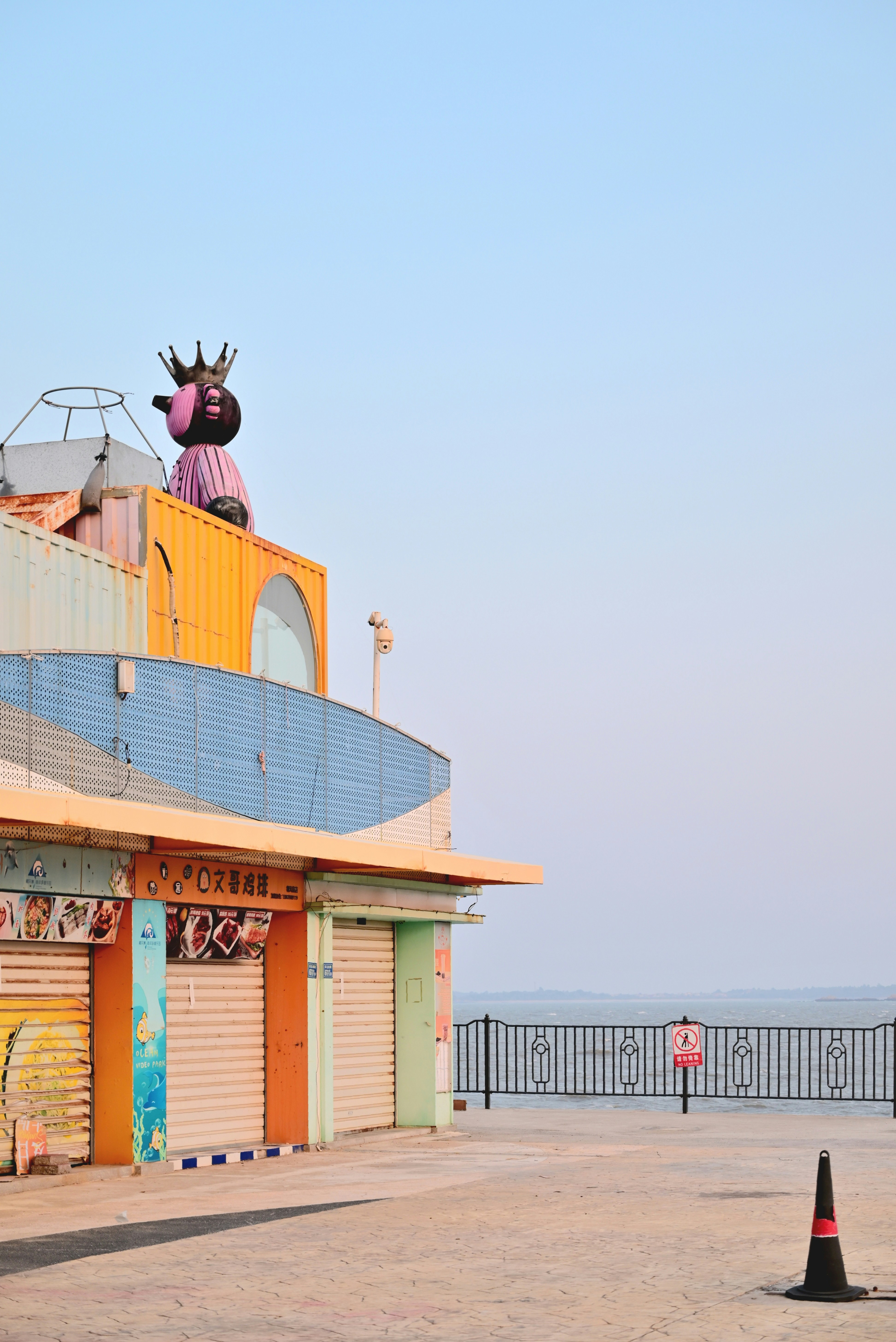 Colorful Waterfront Arcade with Whimsical Rooftop Figure