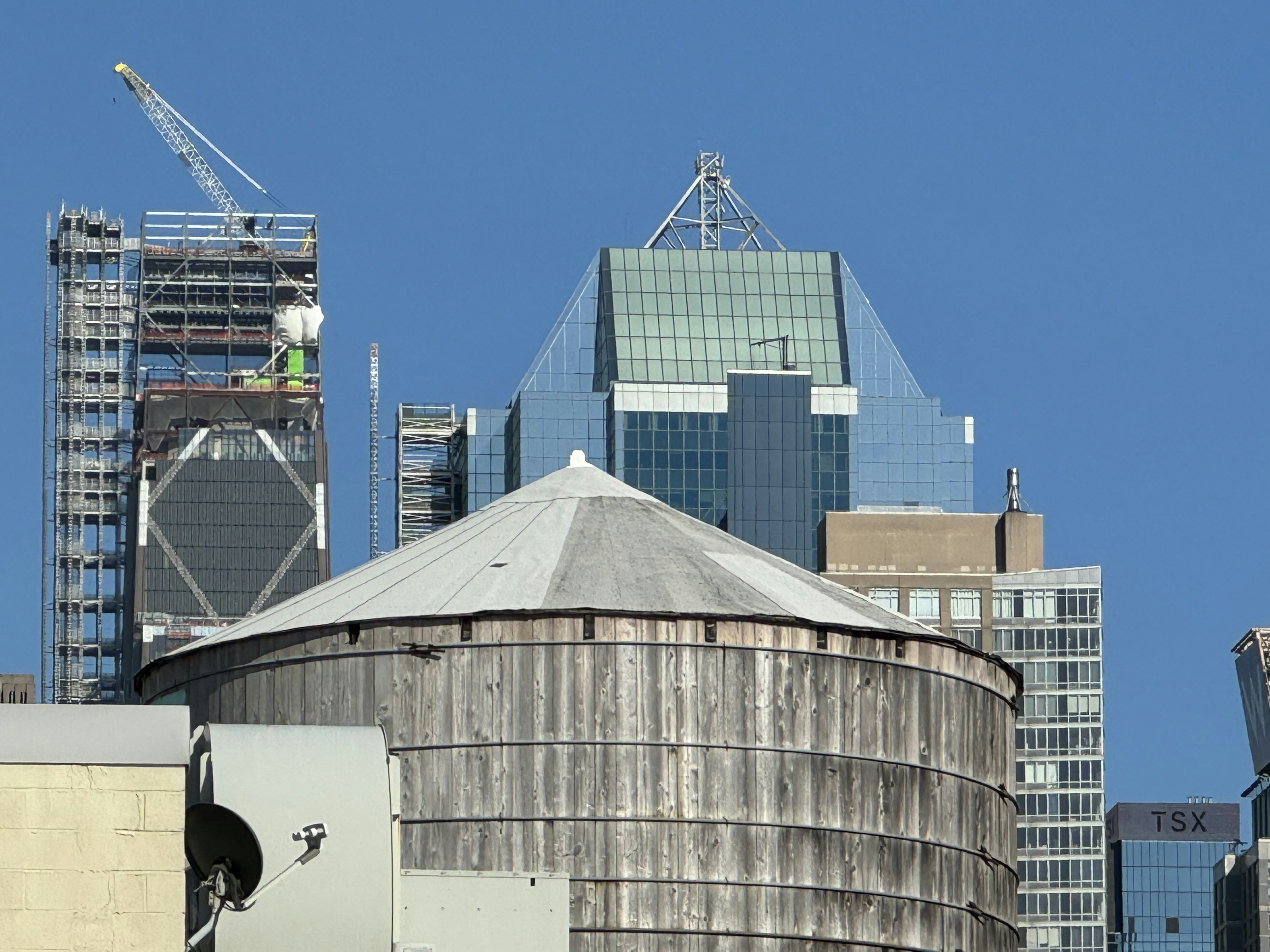 Cranes Behind a Weathered Silhouette: City Core under a Clear Sky