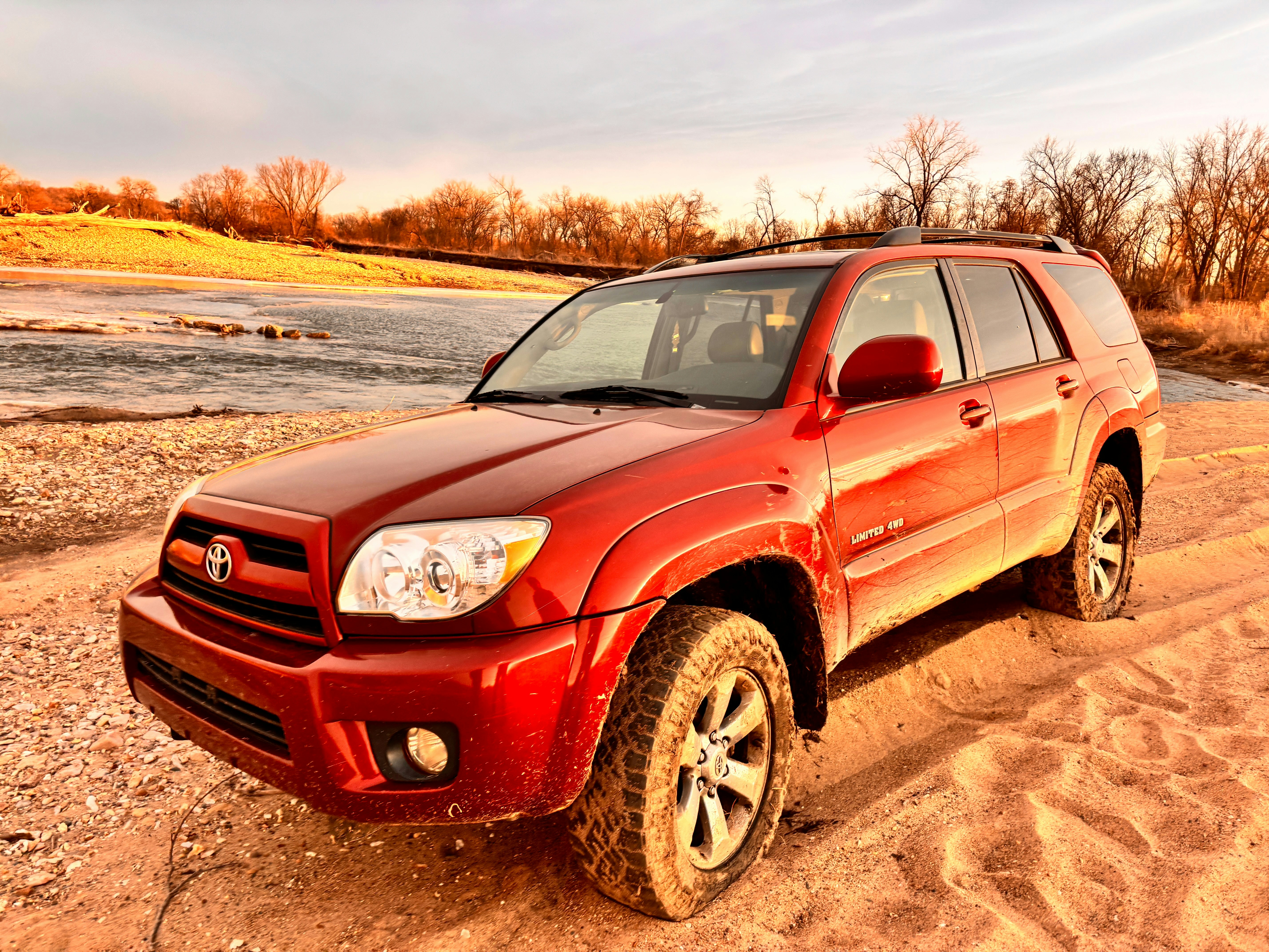 Red Toyota SUV on sunlit riverbank trail