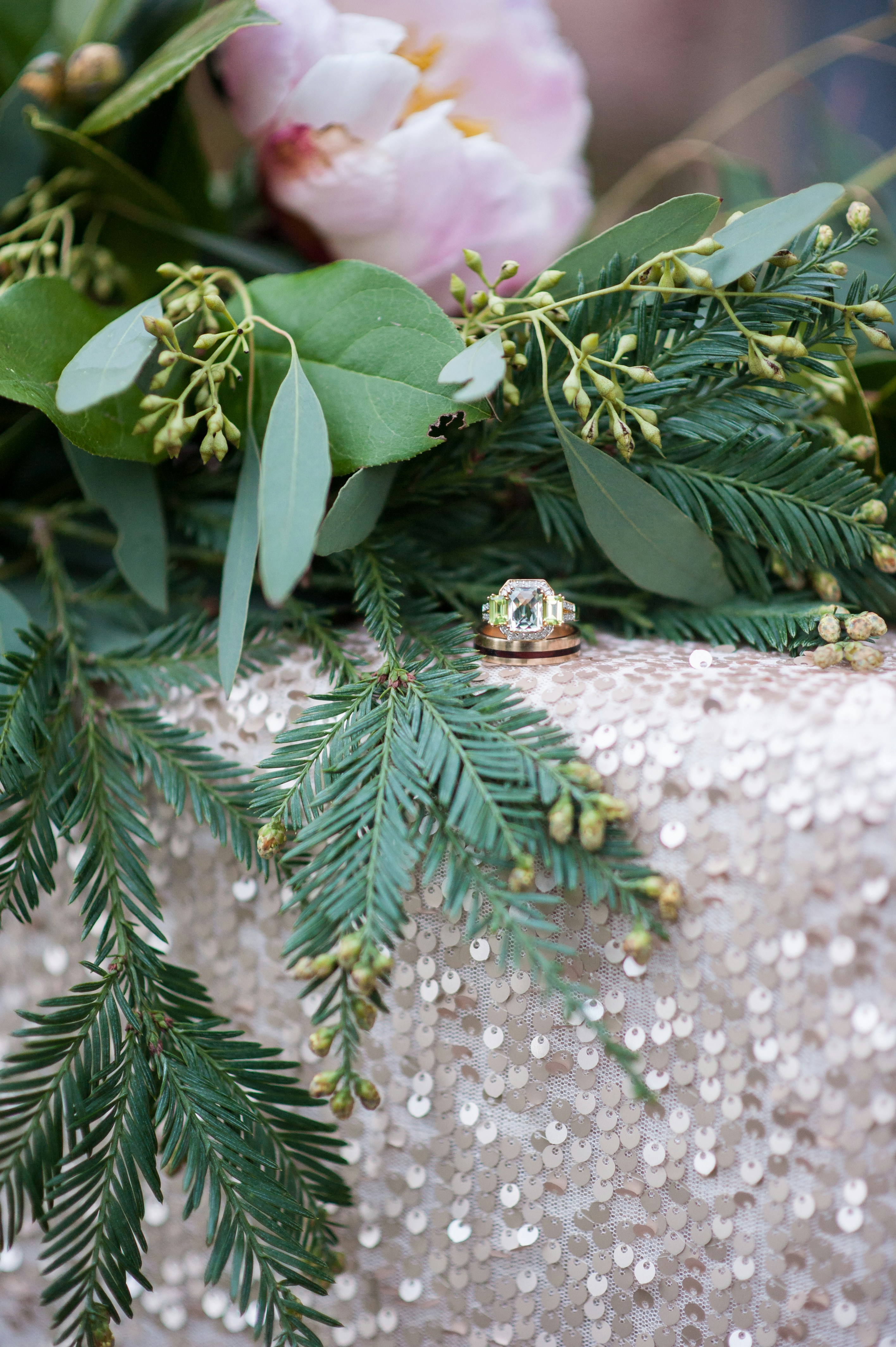 Emerald Ever After: A Gleaming Ring Amid Pine and Petals