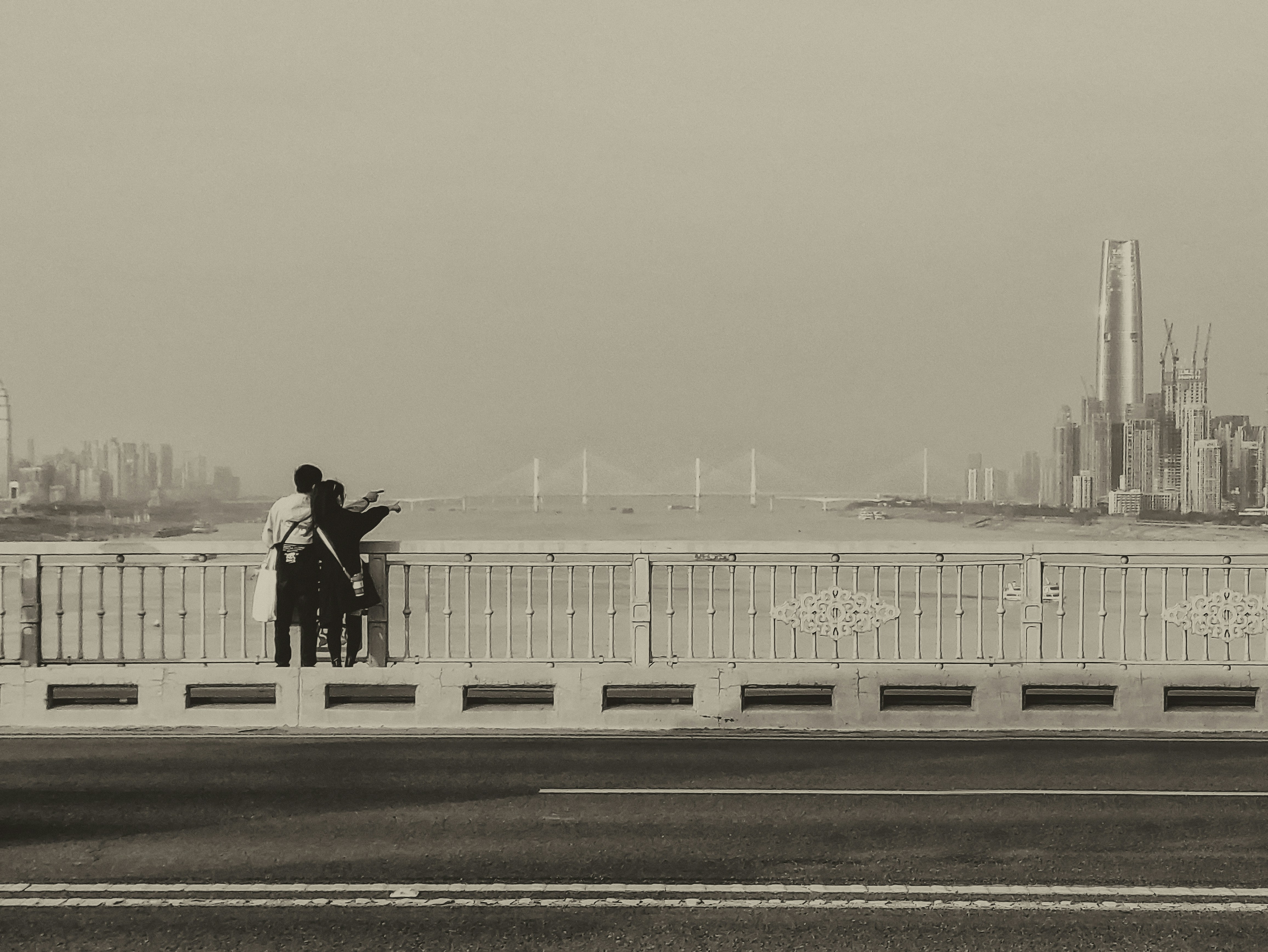 Couple standing on a bridge overlooking a city skyline