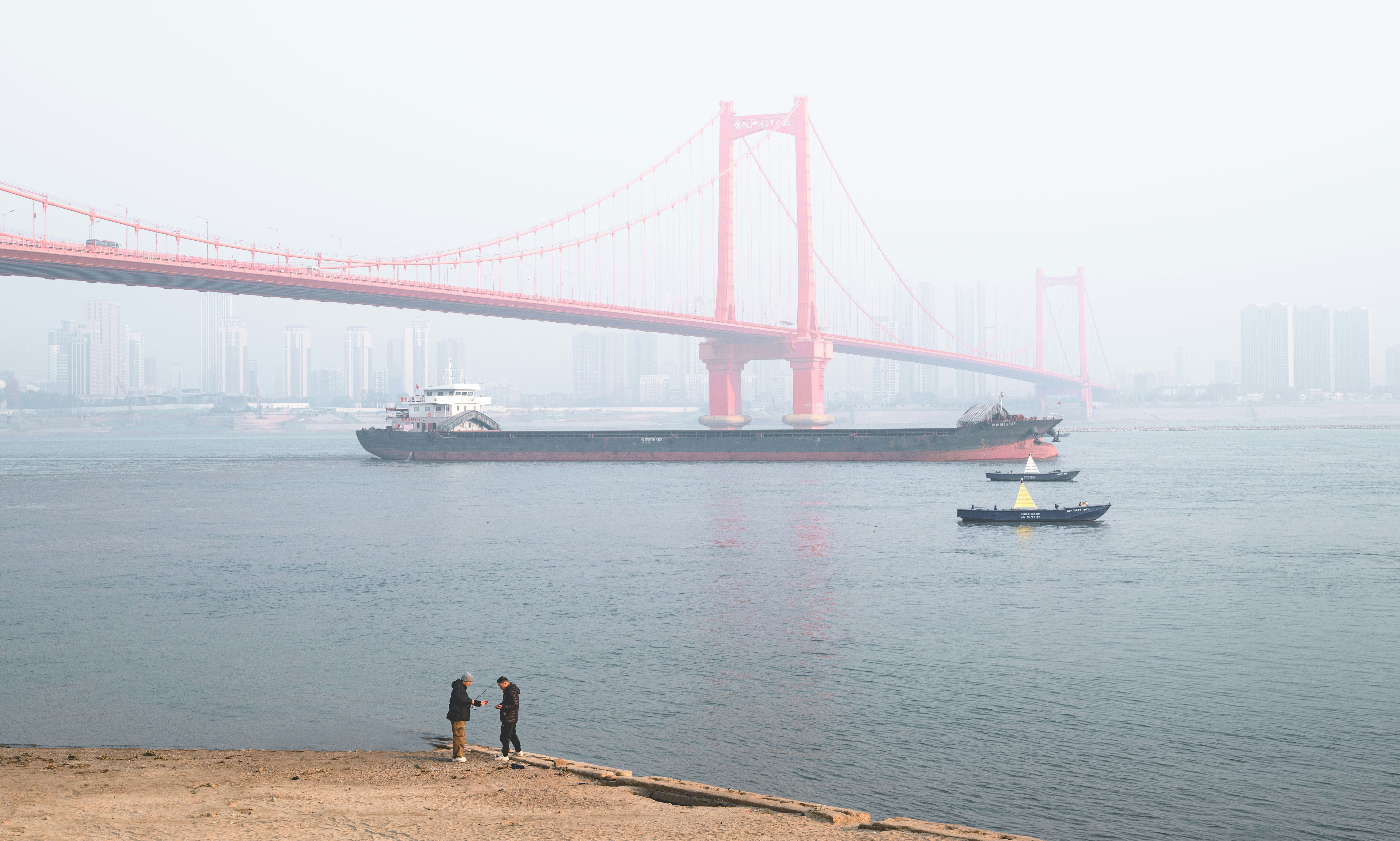 Mist over the River: A Red Cable Bridge and Quiet Shore