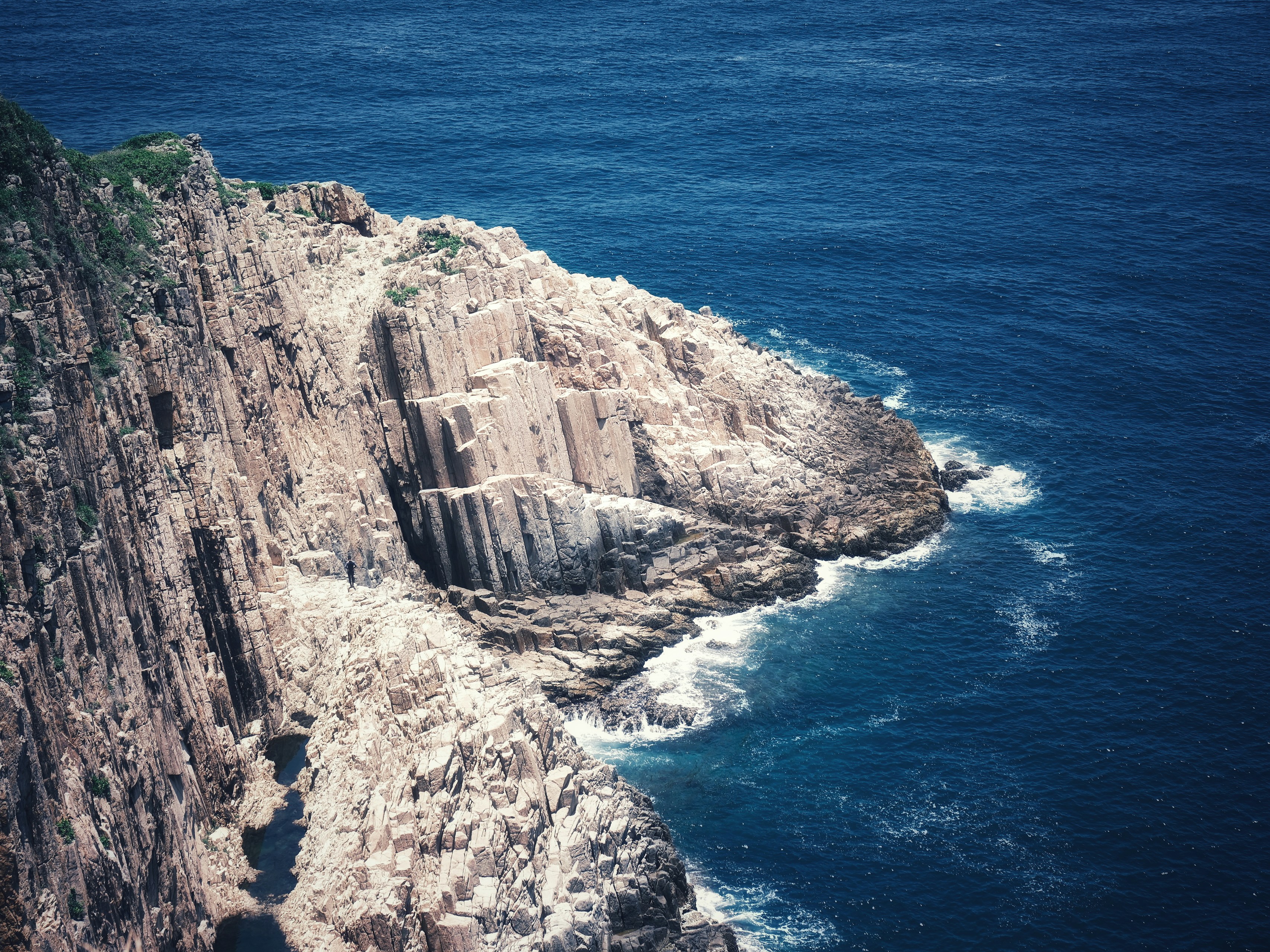 Cliff Edge Cascade: Jagged Rock Coast Meeting Deep Blue