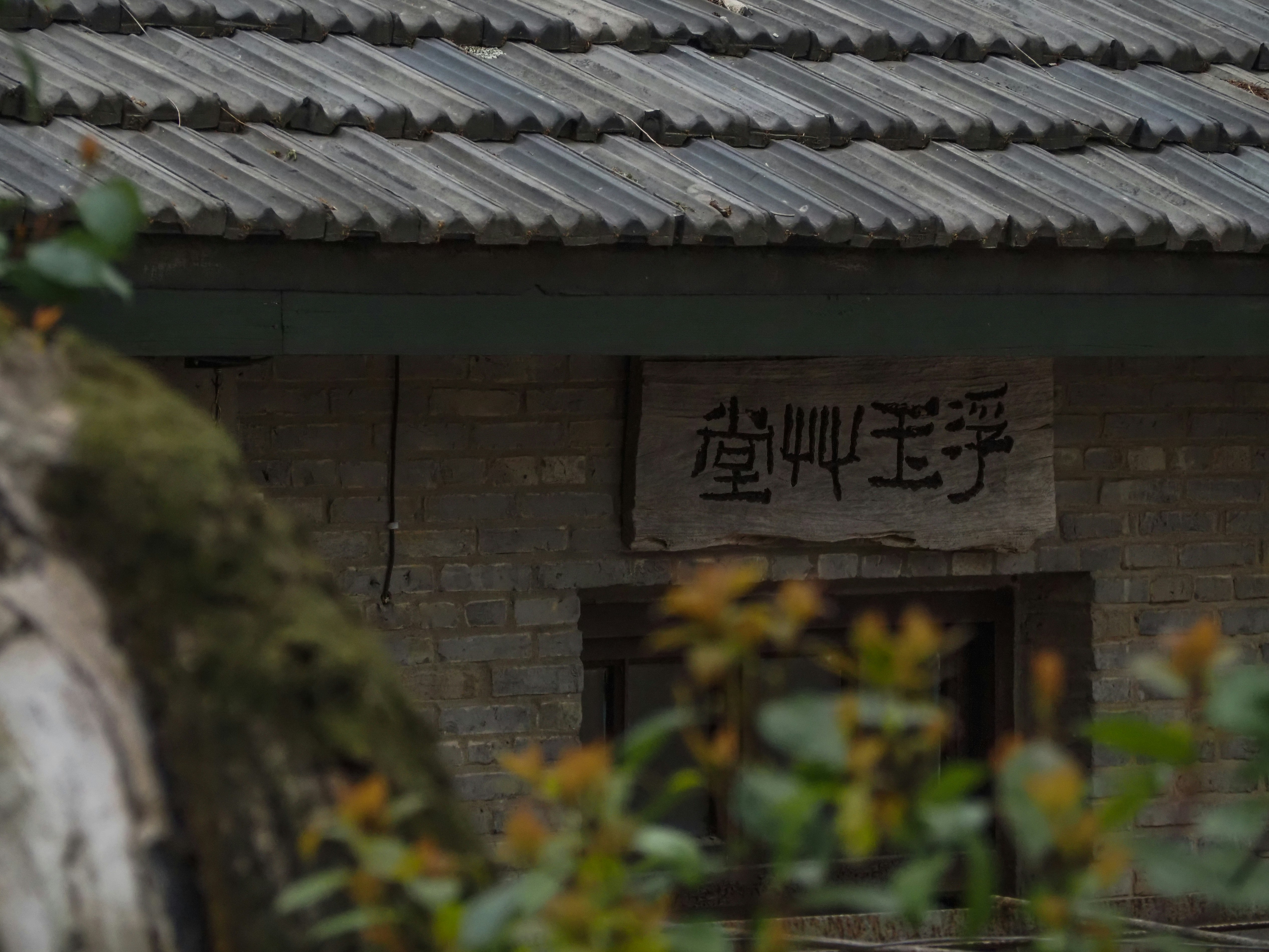 Old Brick Facade Under Tile Roof with Signboard