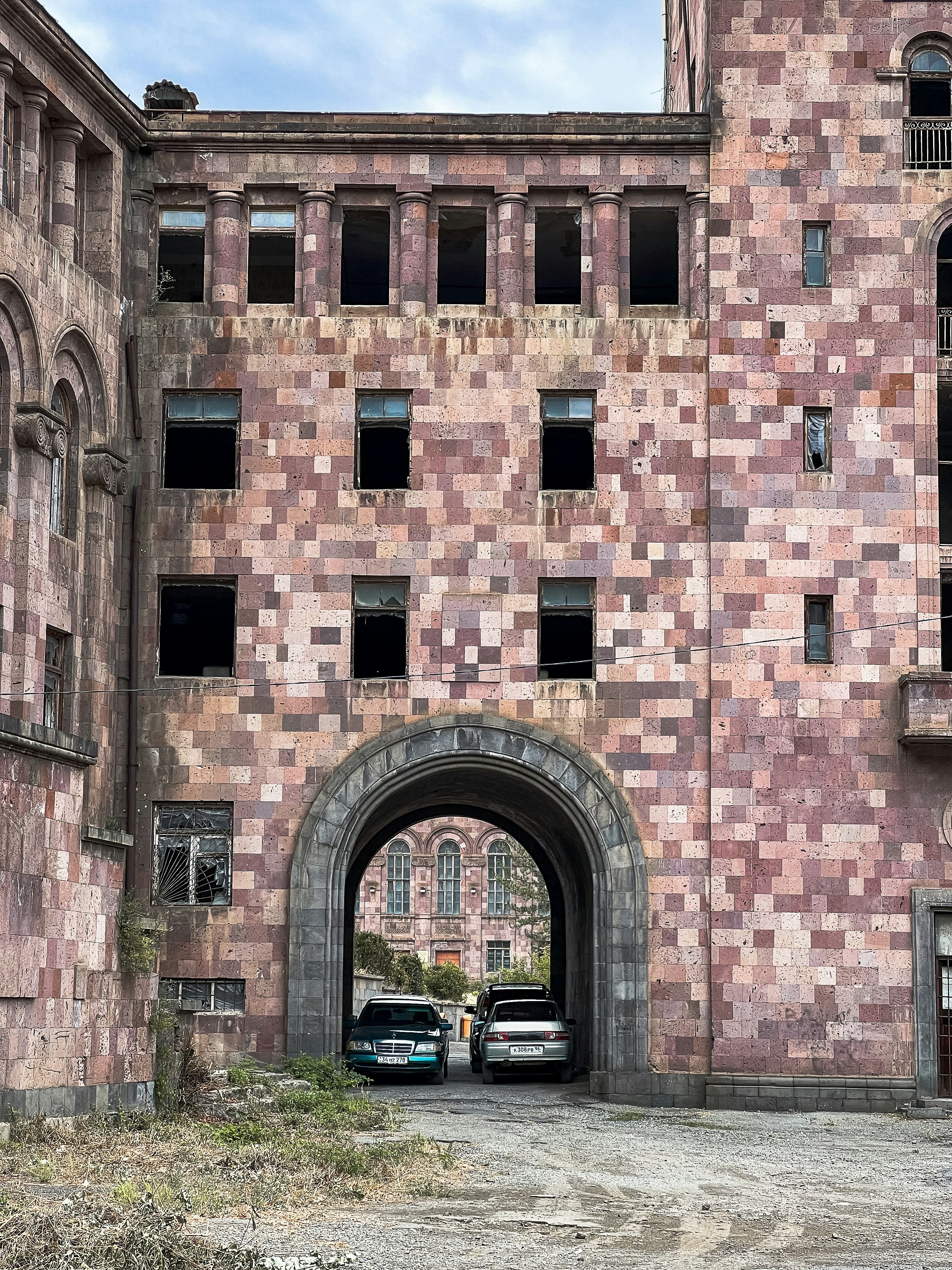 Through the Arch: Cars Rest in the Ruins of a Pebble-tiled Facade