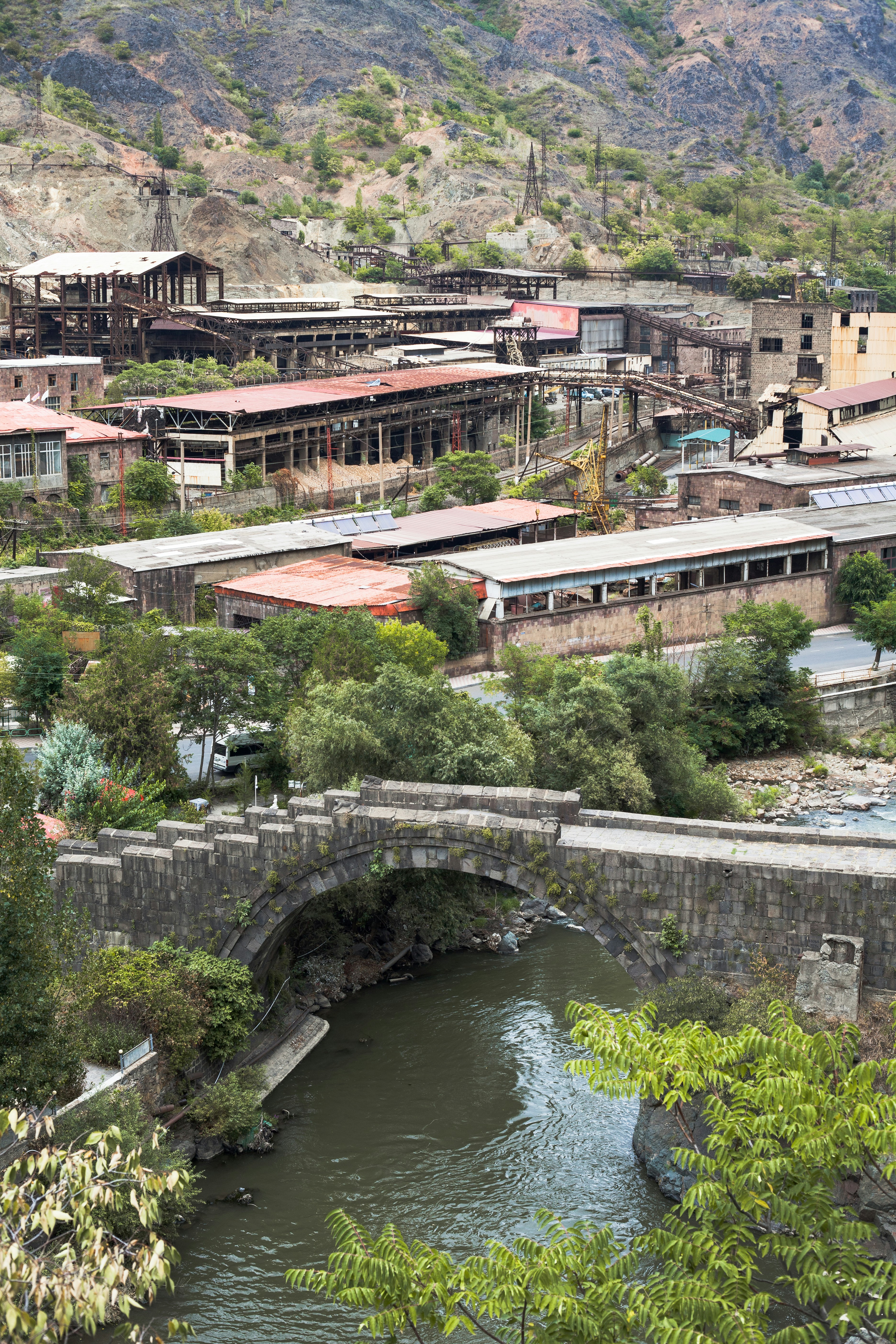 Stone Archway Over a Quiet River Framing a Distant Industrial Terrace