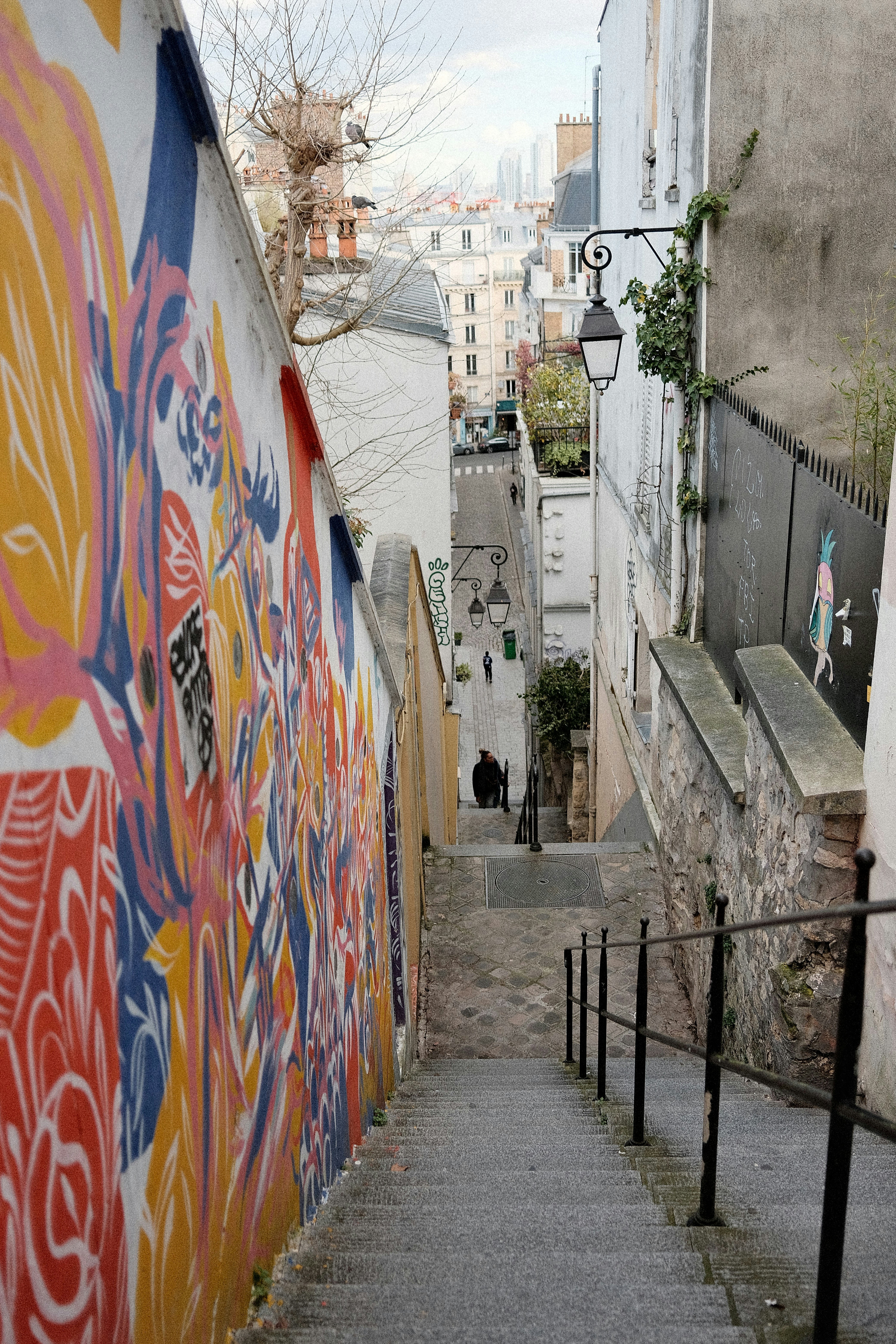 Descending toward the city: a graffiti-lined stairway to distant rooftops