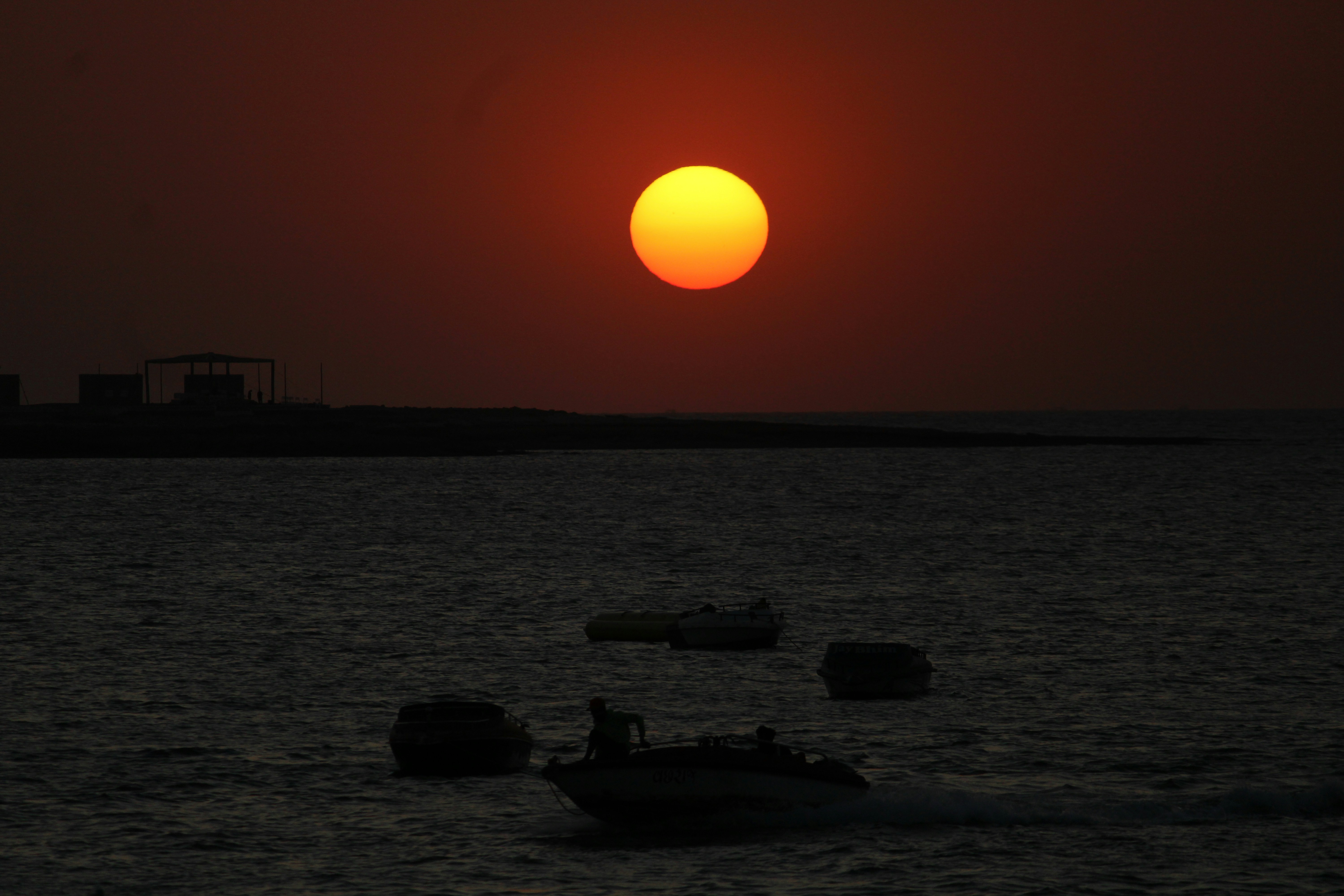 Sunset Sentinel: Boats Drape the Horizon in Silhouettes