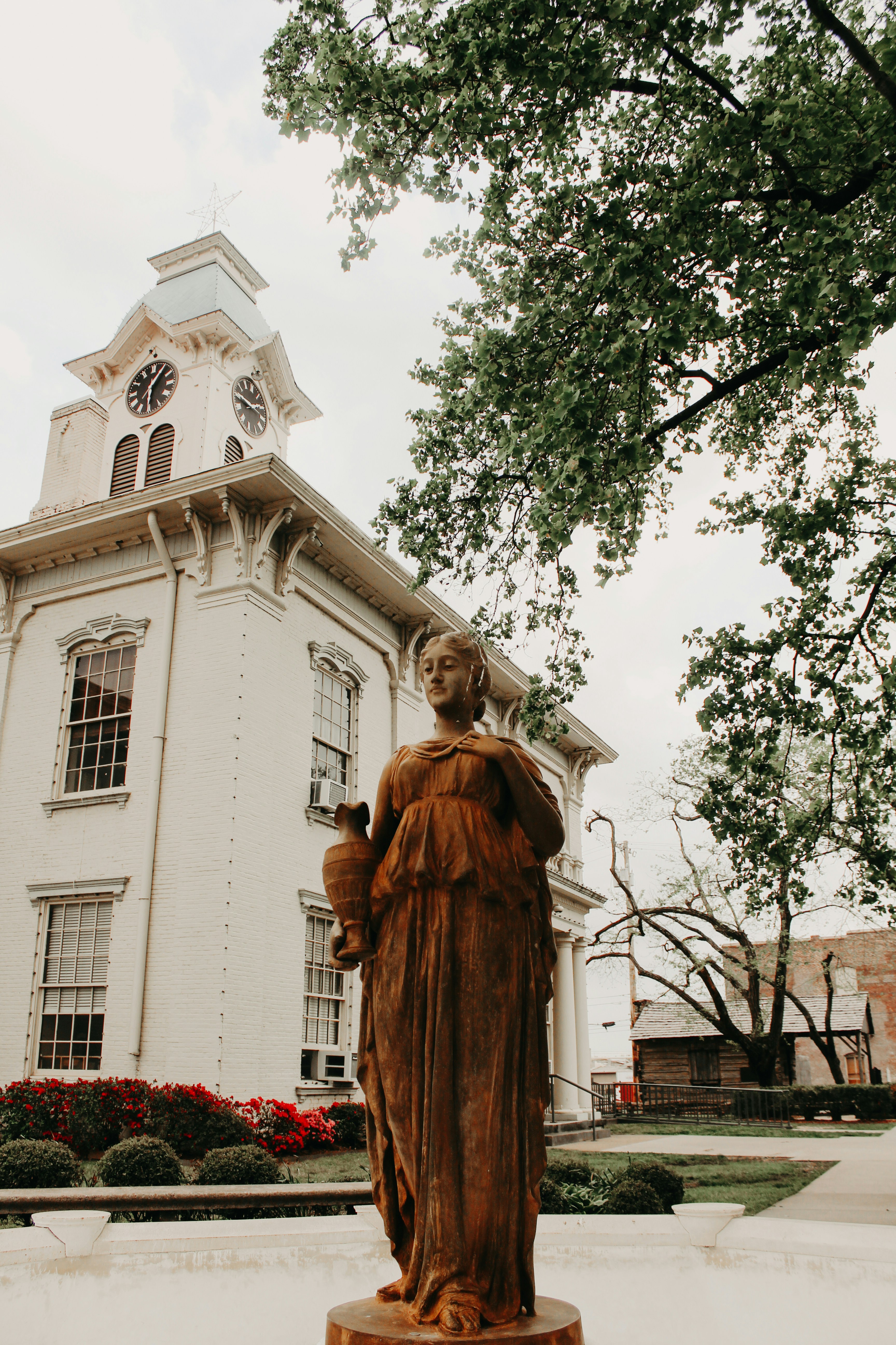 Statue in a Courtyard: A Bronze Figure Framed by a White Clock Tower
