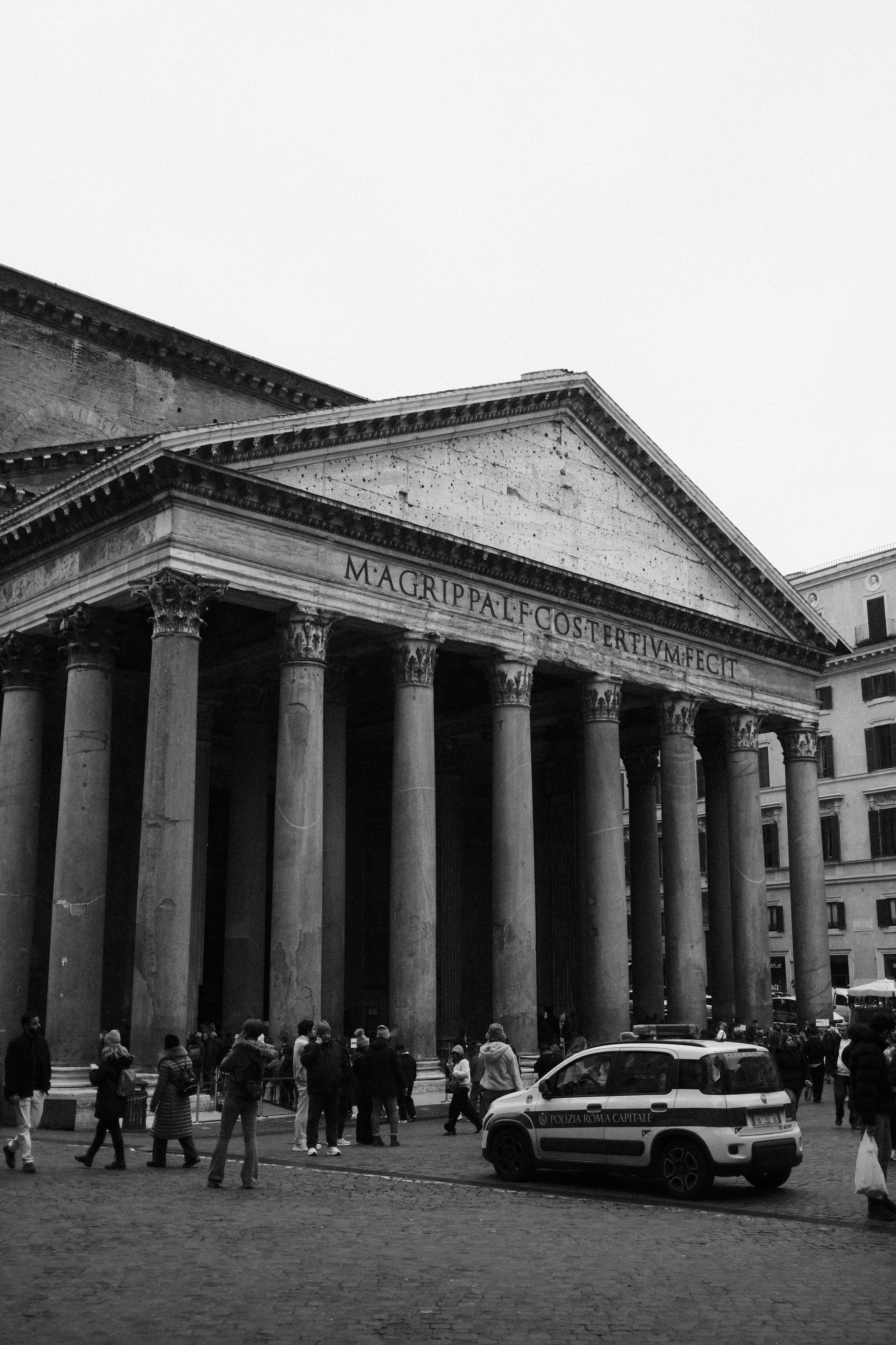 Temple of Pedestrian Scale: A Neoclassical Facade Framed by People and a Police Vehicle