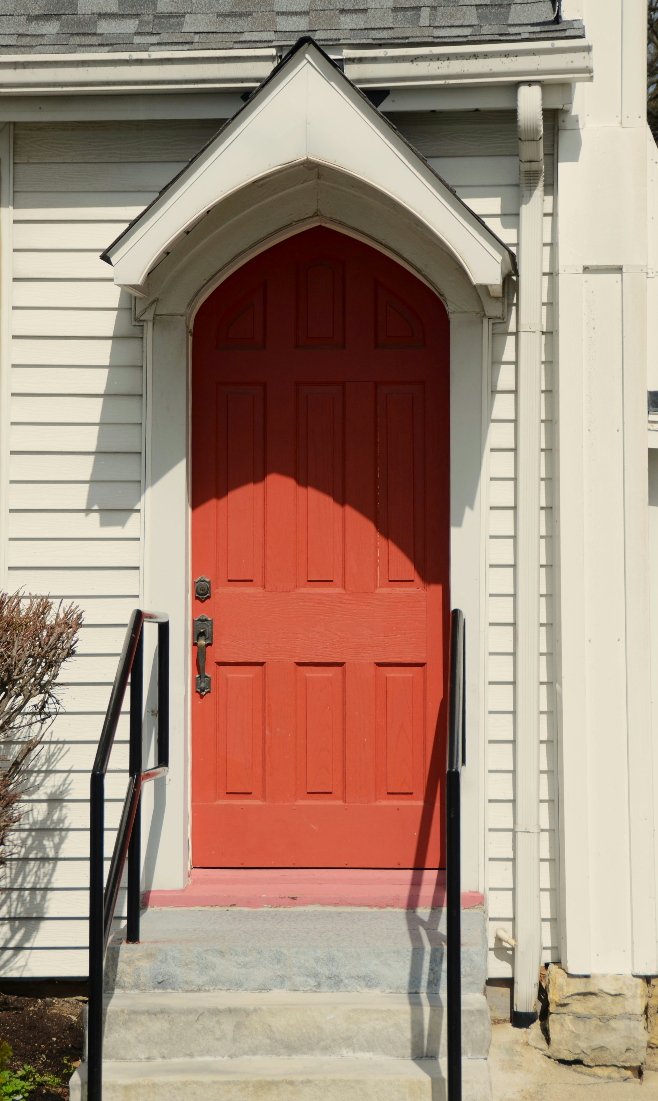 Red Door Framed by White Siding and Steps