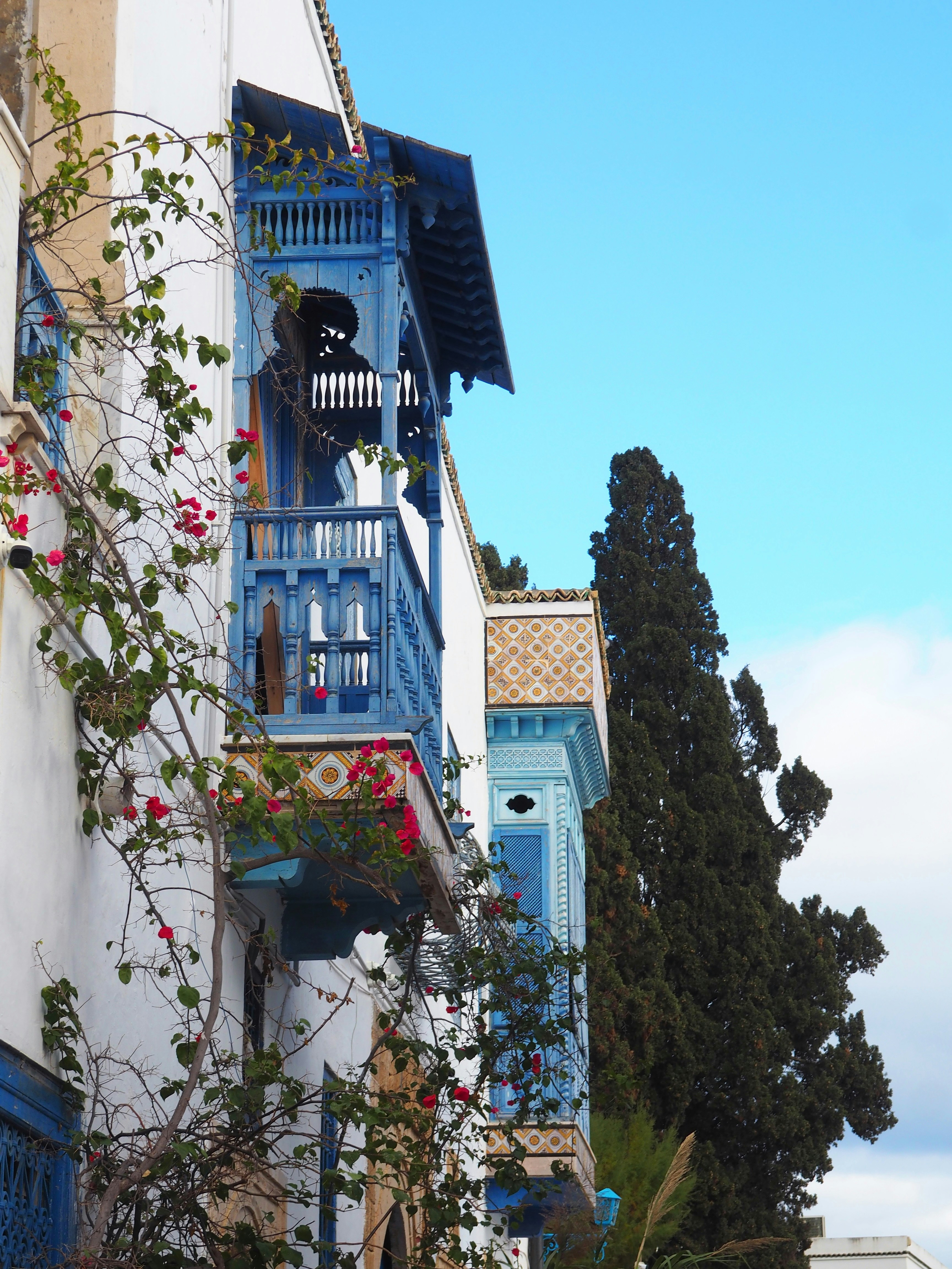 Blue Balcony Echoes: Carved Windows and Bougainvillea in a Moroccan-Style Alley