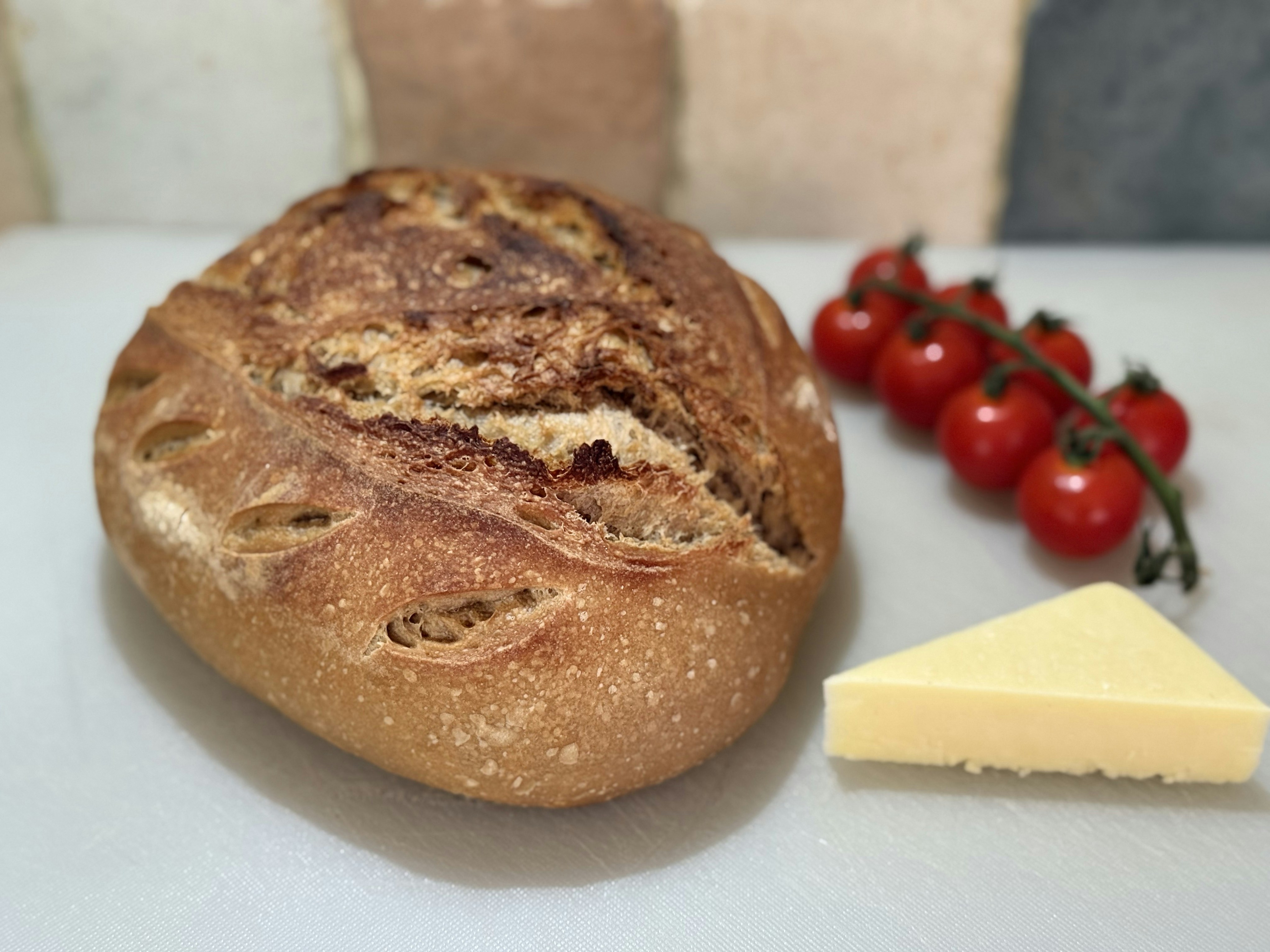 Crusty Boule with Butter and Cherry Tomatoes on a Light Board