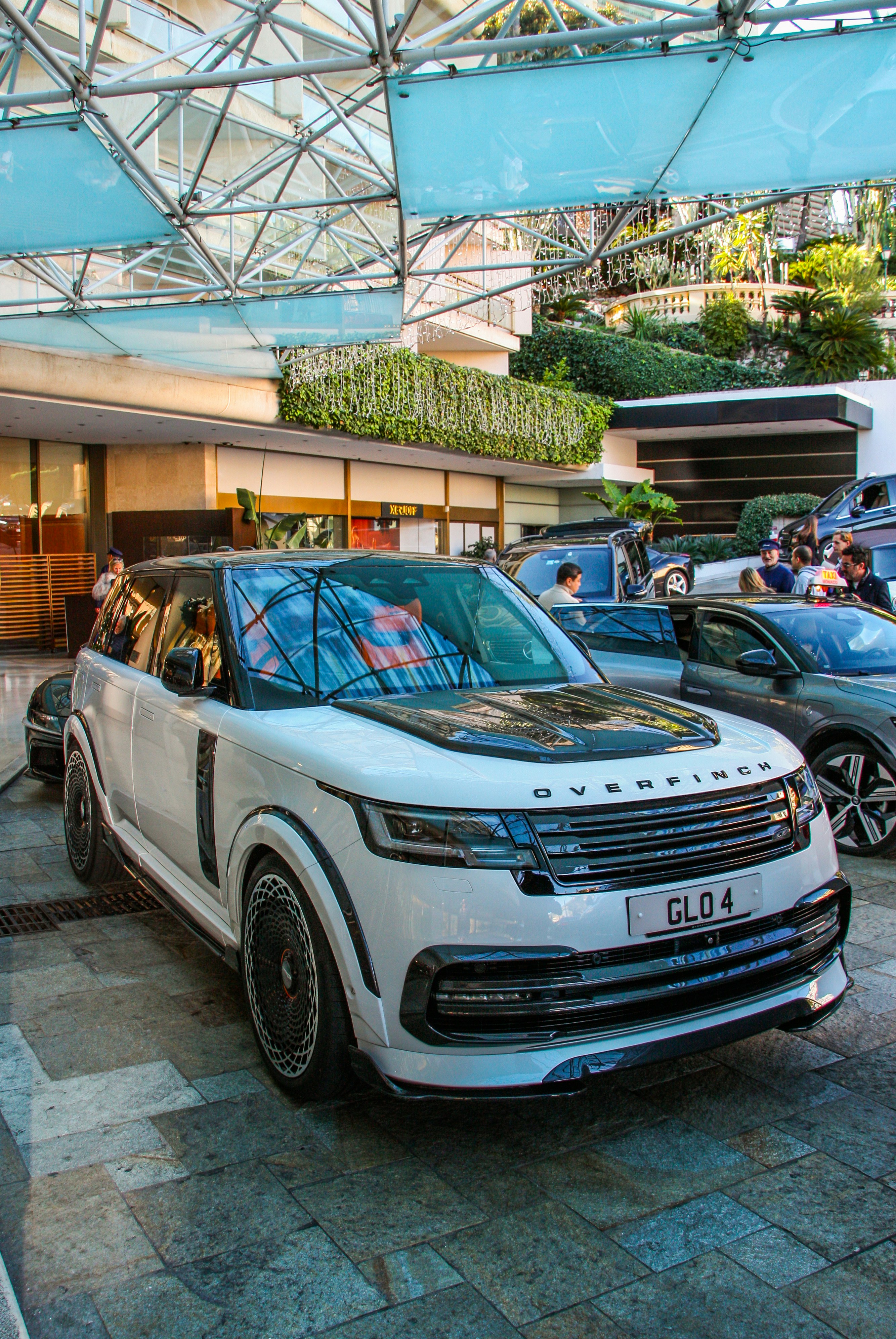 White SUV in a glass-canopied hotel forecourt