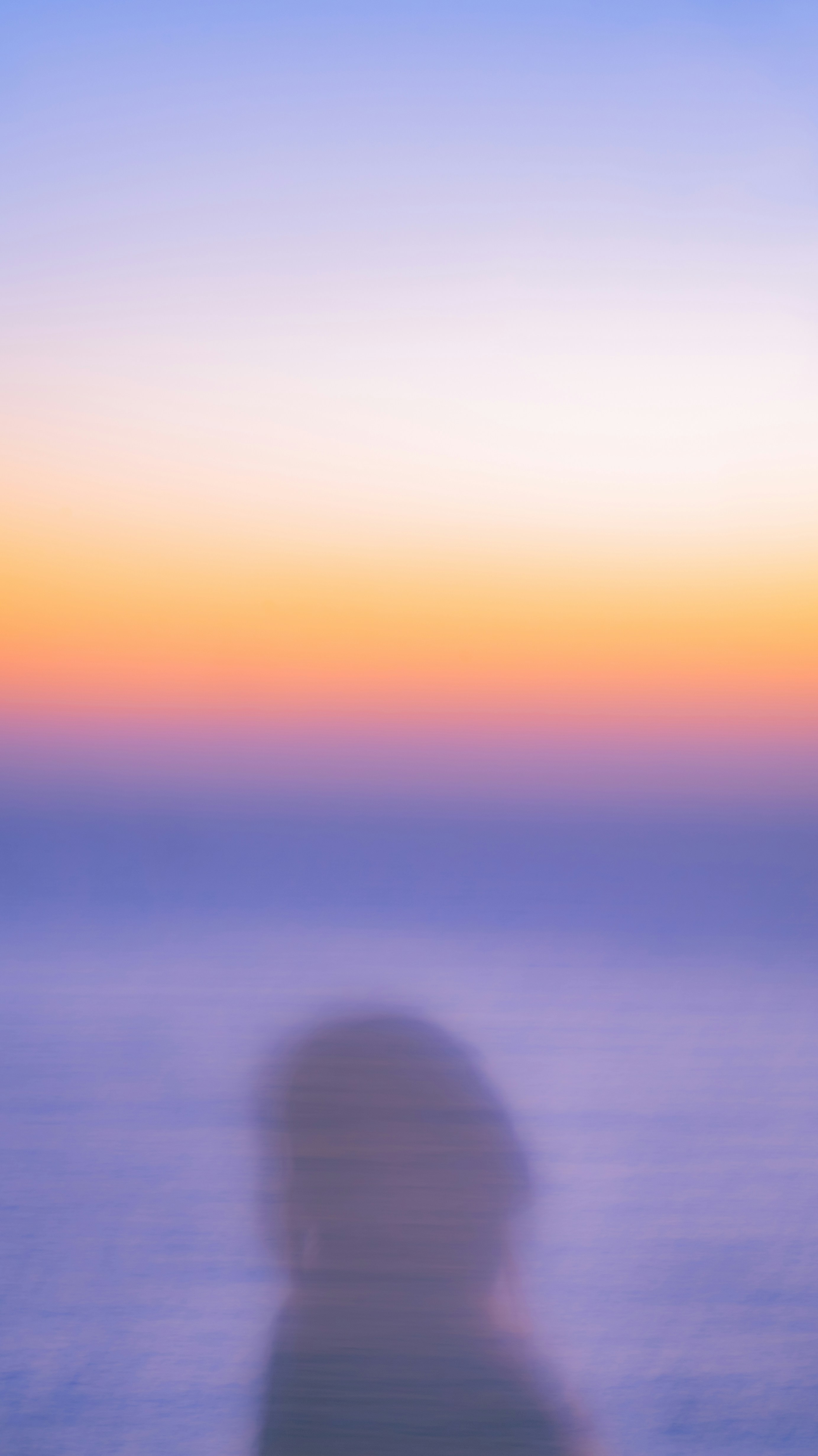 Hazy Horizon: A Silhouetted Moment Over Quiet Waters at Dusk
