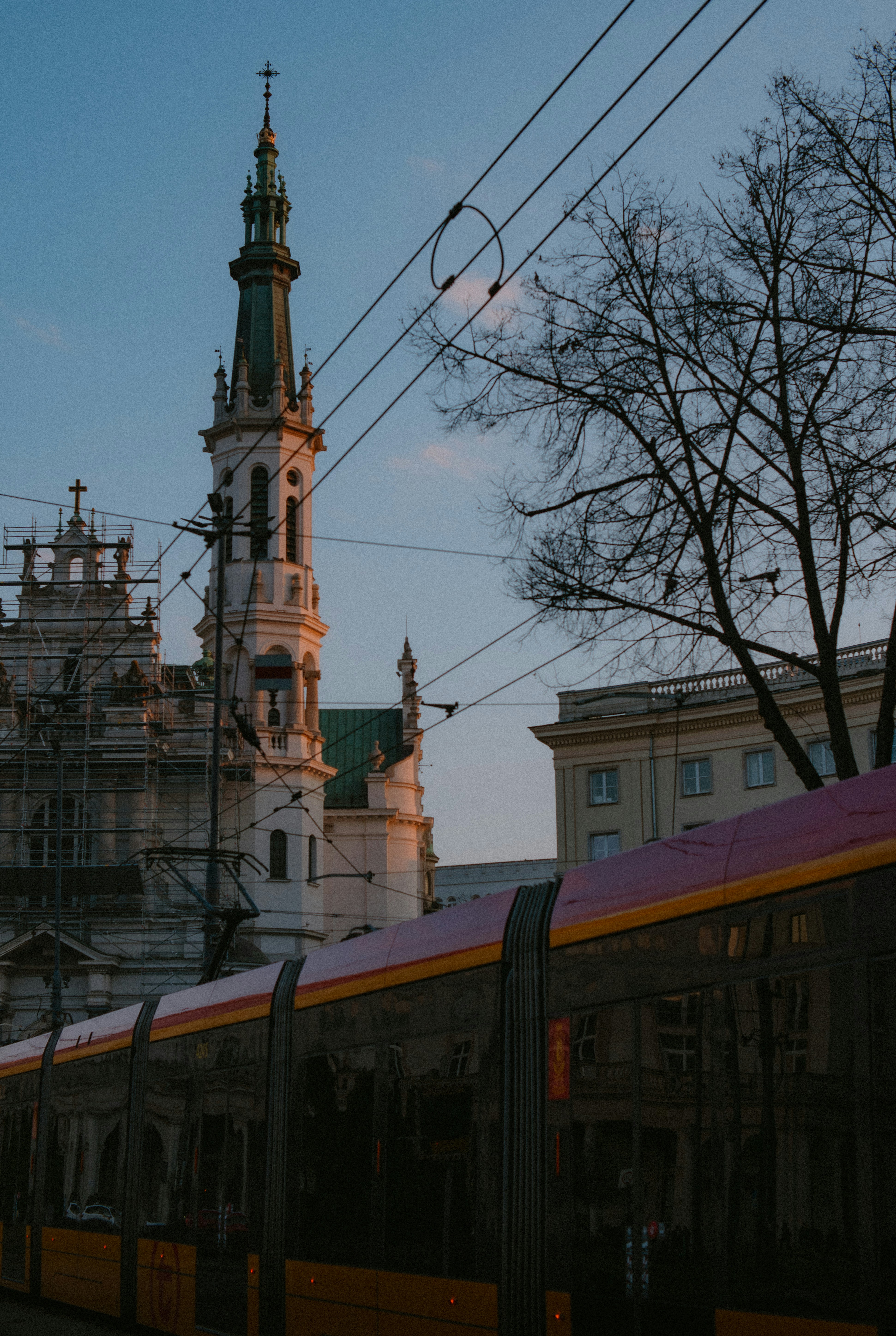 Sunlit spire and tramlines: winter city silhouette at dusk