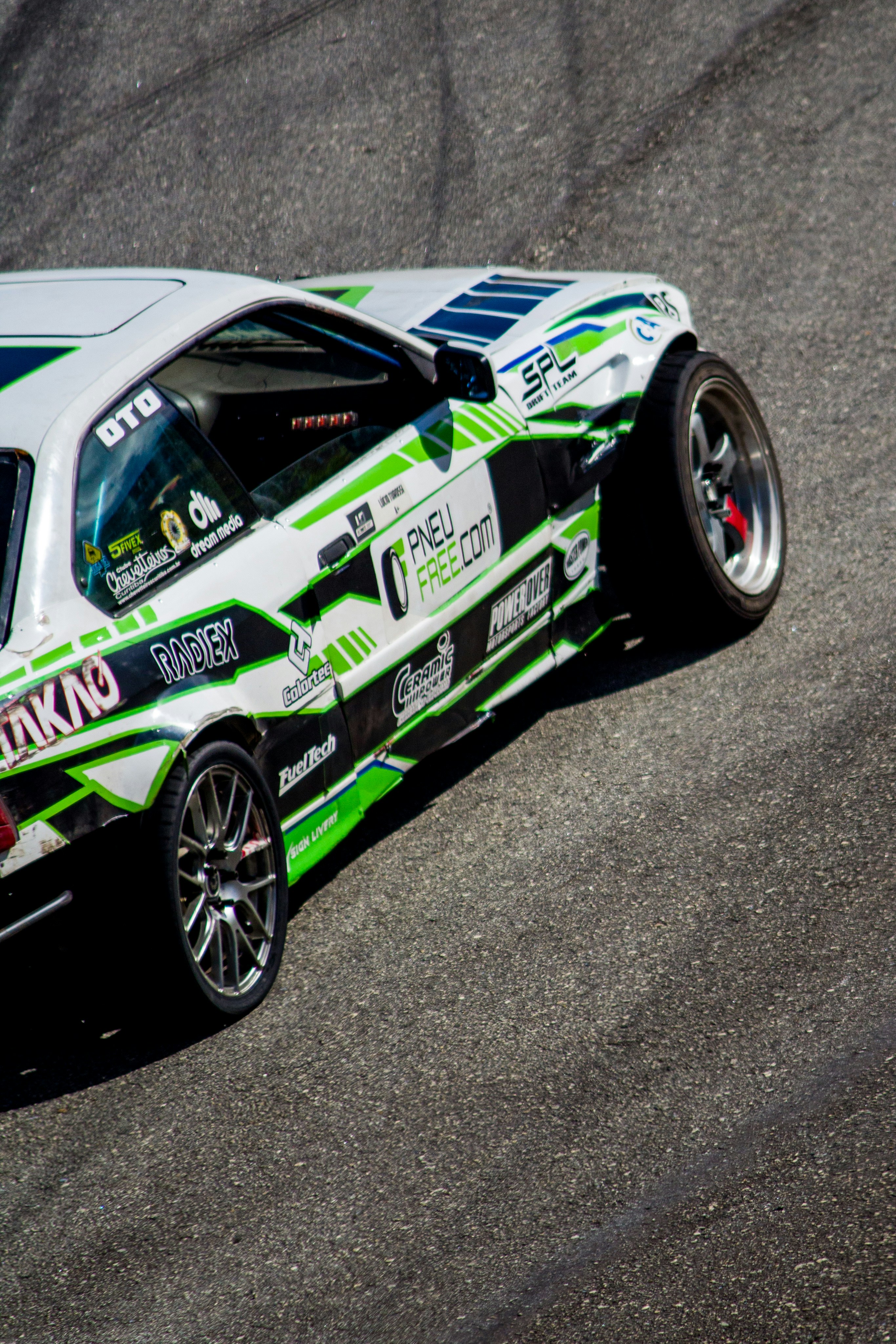 Racing Machine in Focus: Green-White Livery Crossing the Asphalt